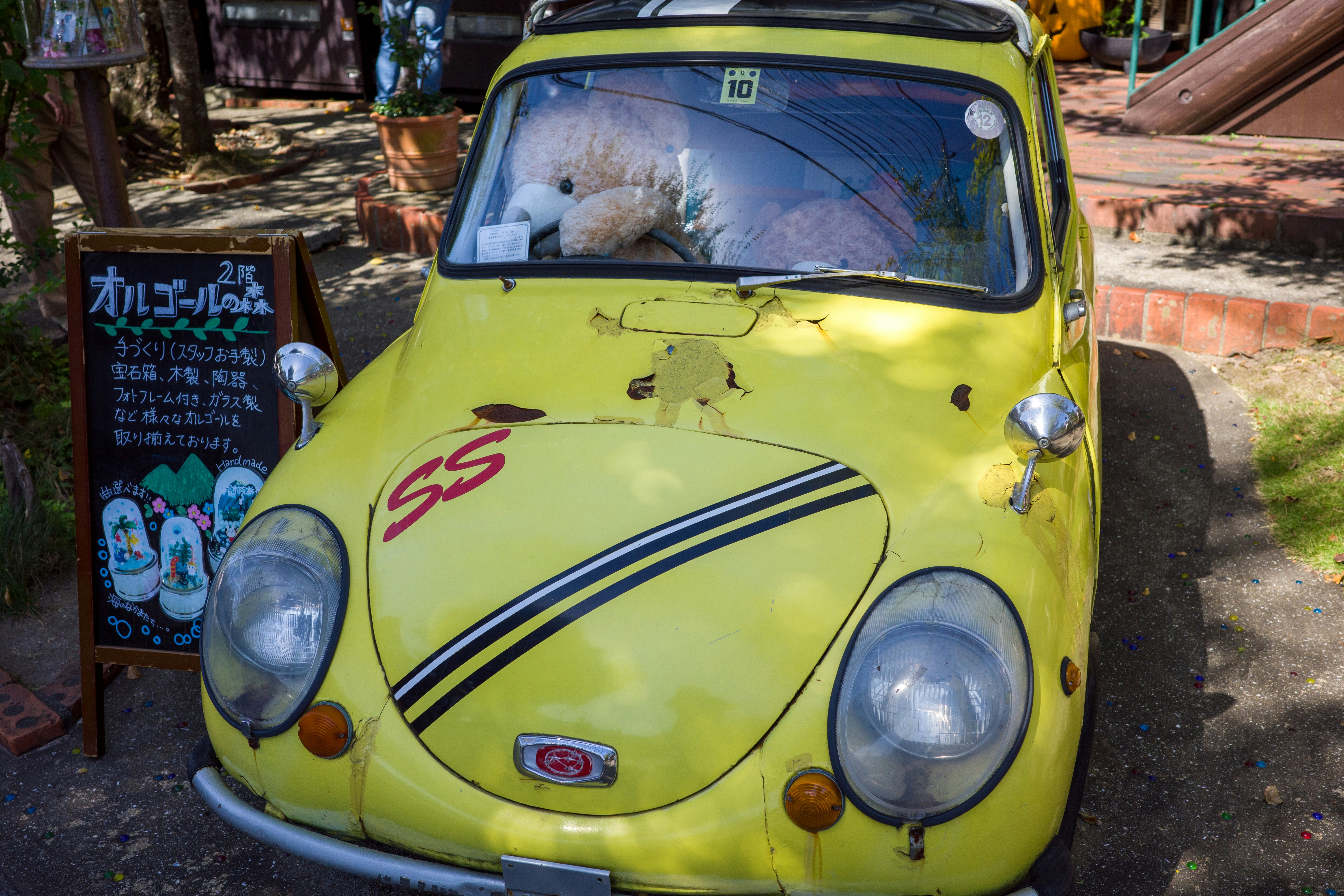 Sunlit Yellow Classic: A Weathered Smile on a Tiny Car