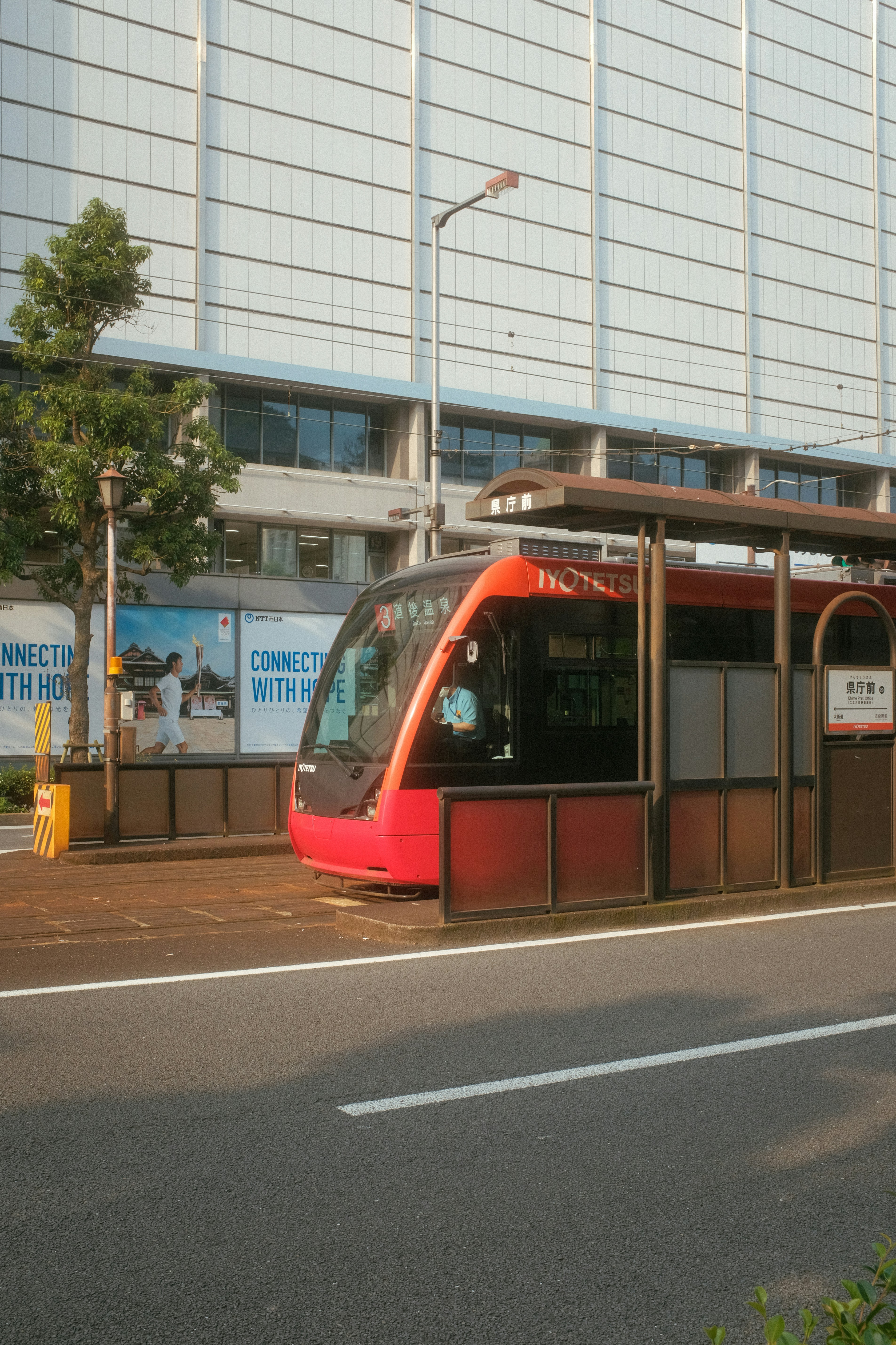 Crimson Streetcar at the Glass-Fronted City Edge