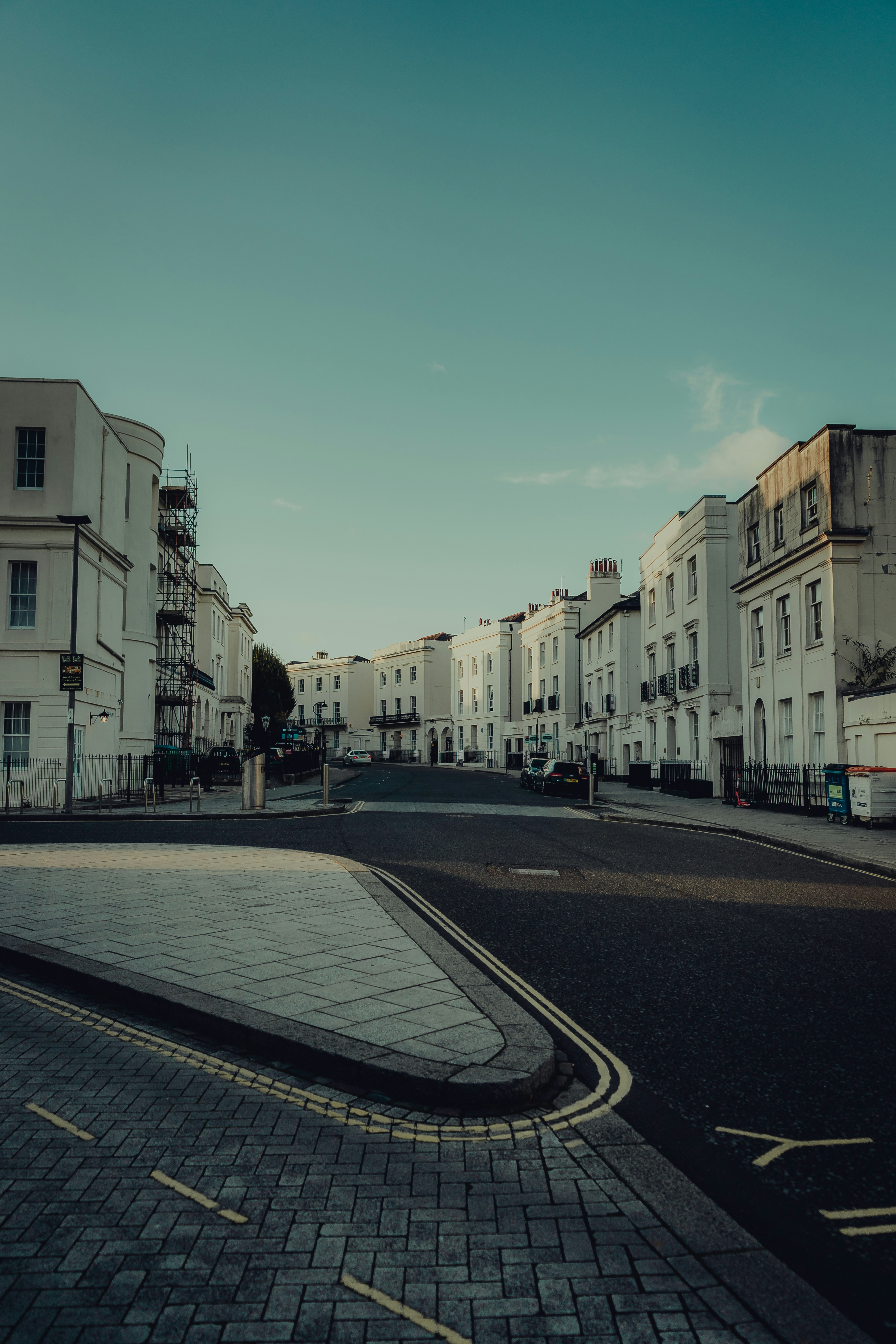 Charming street scene featuring white buildings lining a tranquil urban intersection. The soft blue sky enhances the peaceful atmosphere.