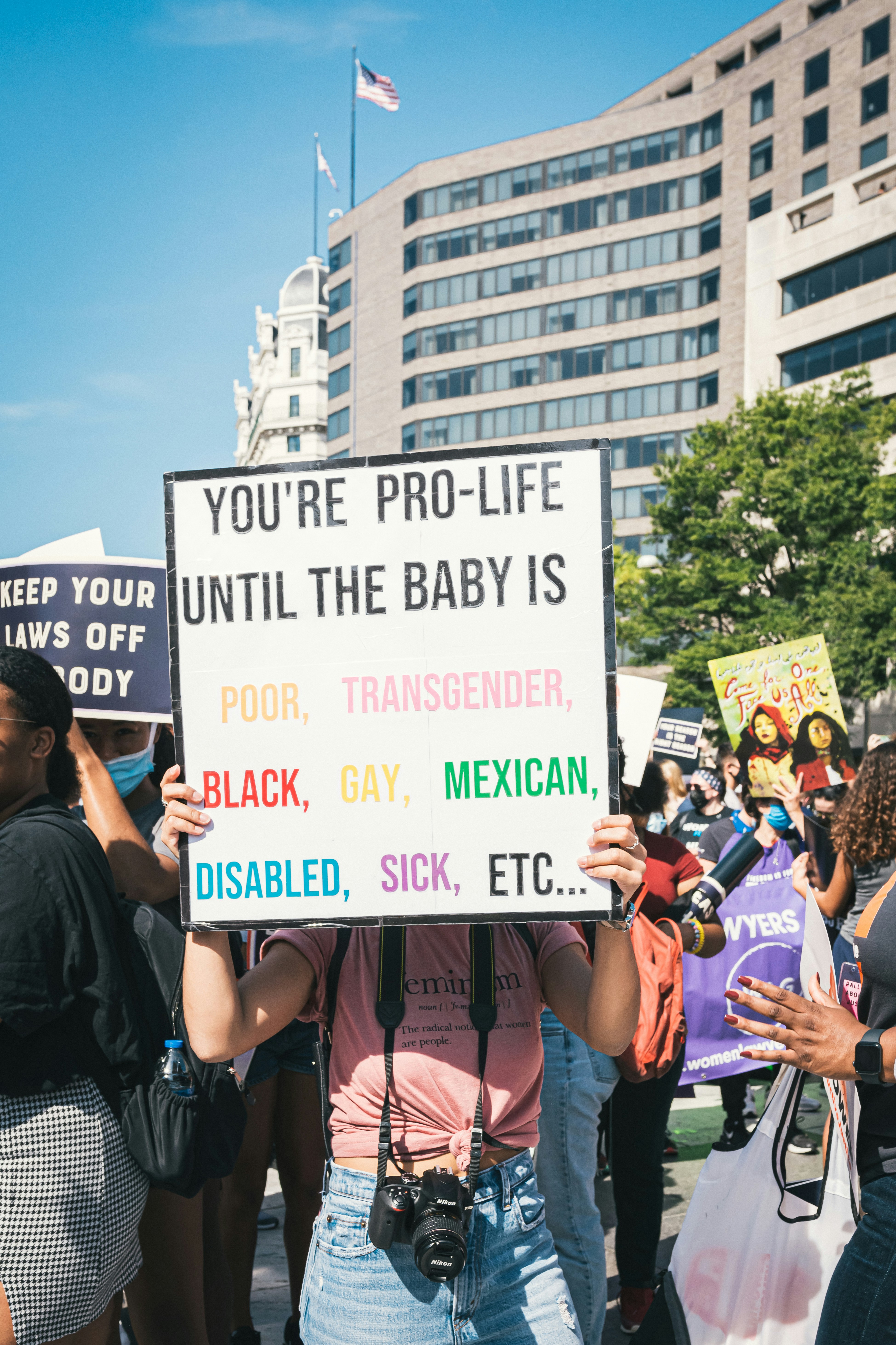 A woman holding a sign that says you're pro - life until the baby photo ...