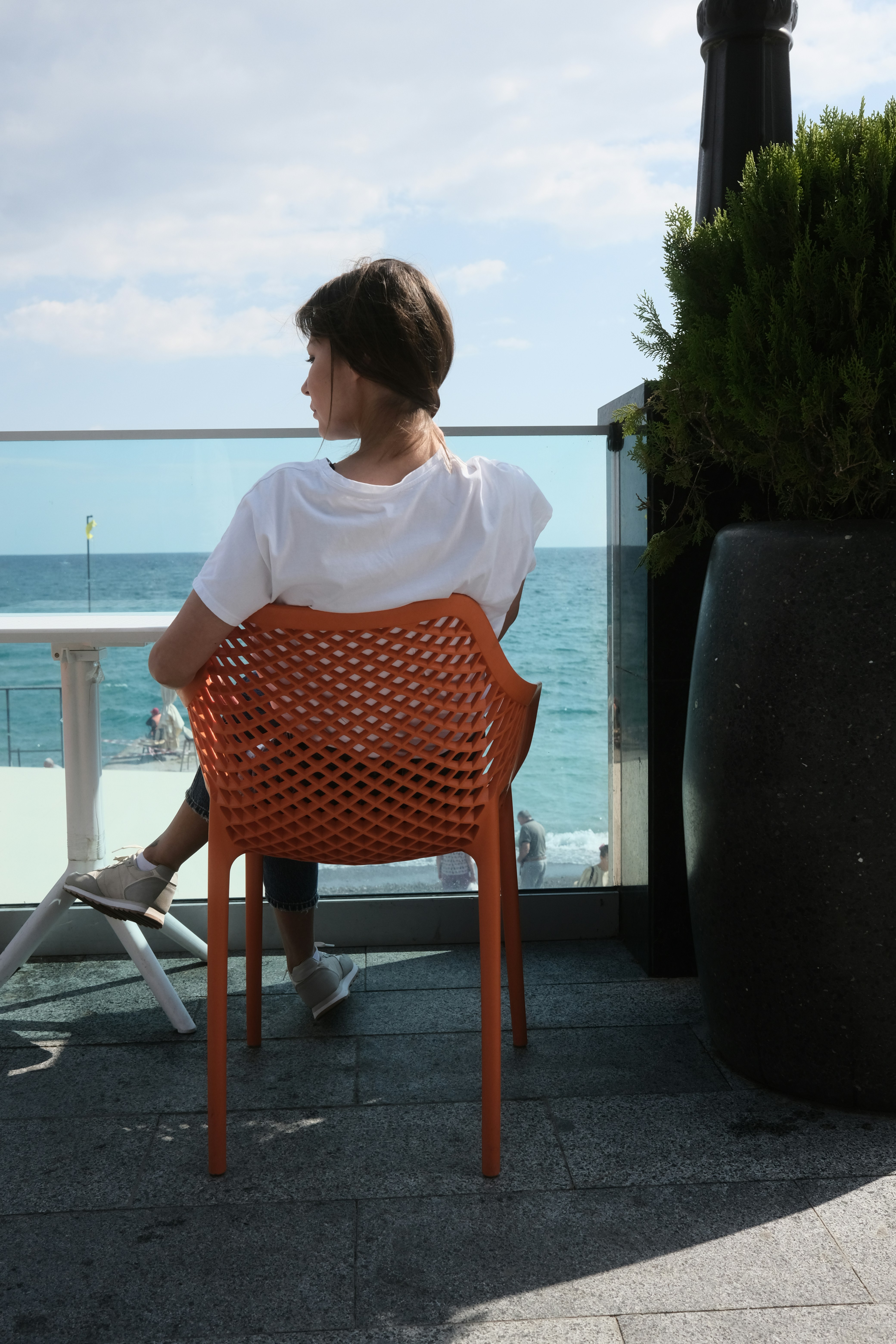 a woman sitting on a chair looking out at the ocean
