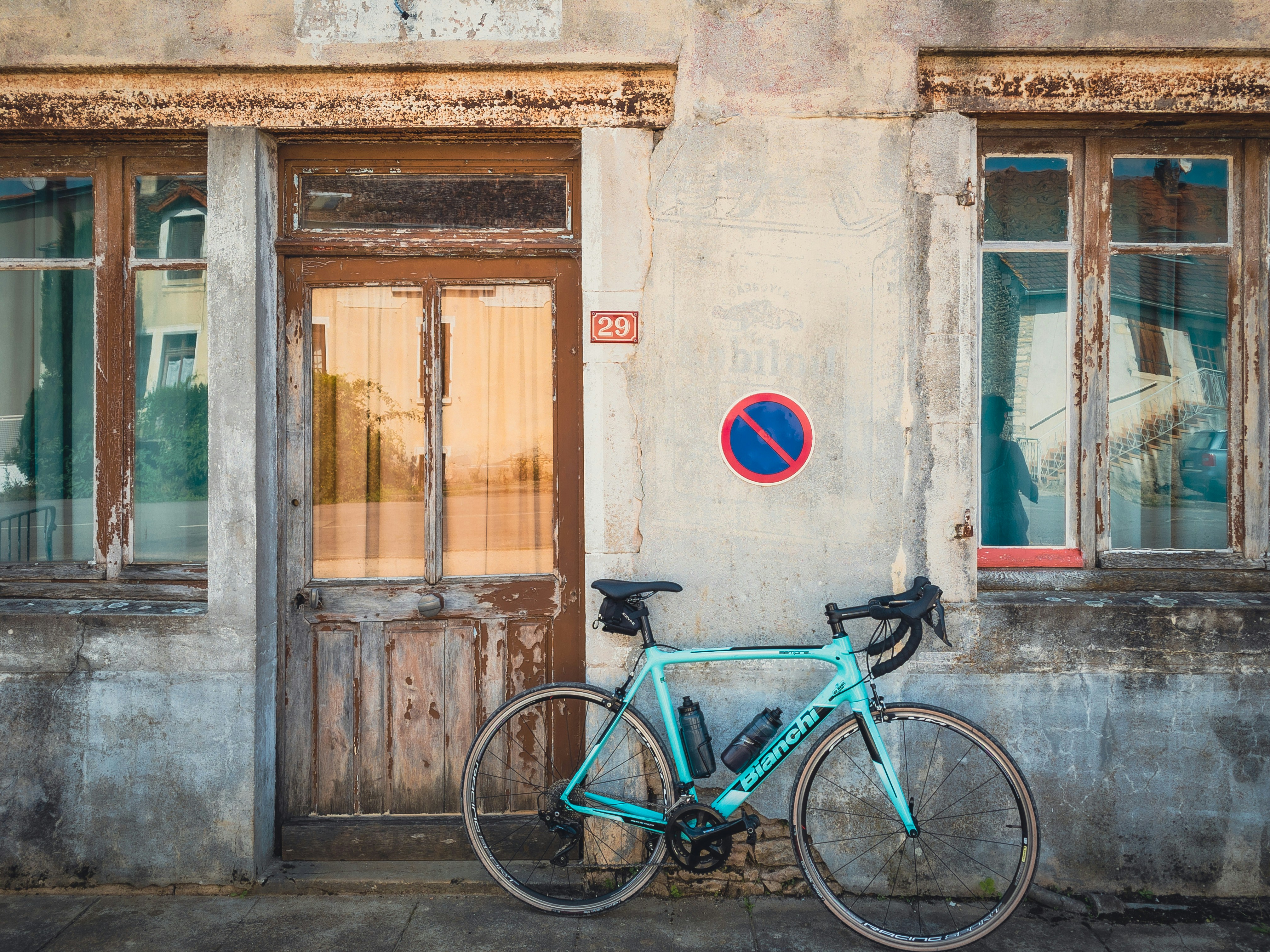 Turquoise Road Bike Anchored to a Timeworn Facade