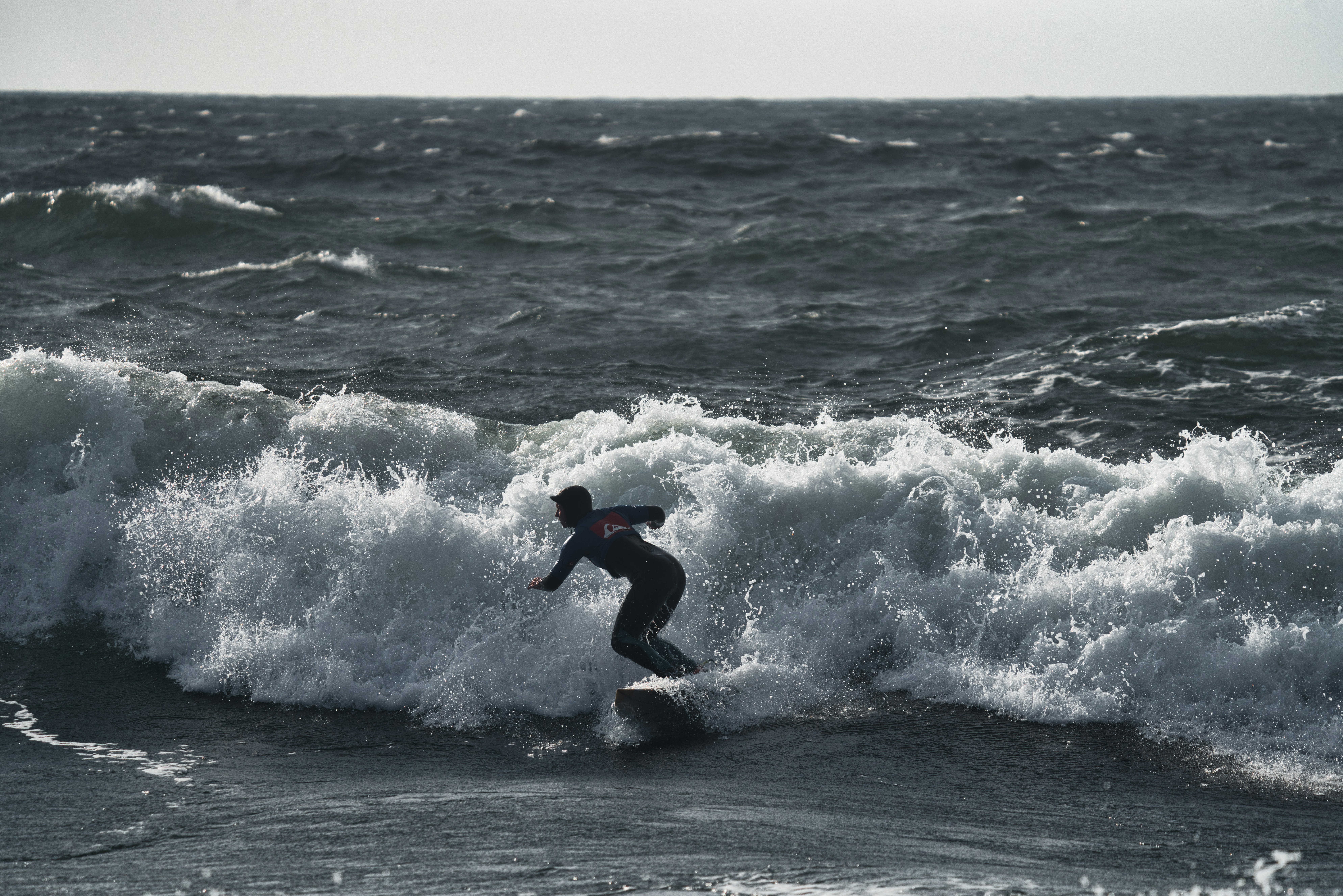 Um homem cavalgando uma onda em cima de uma prancha de surf foto ...