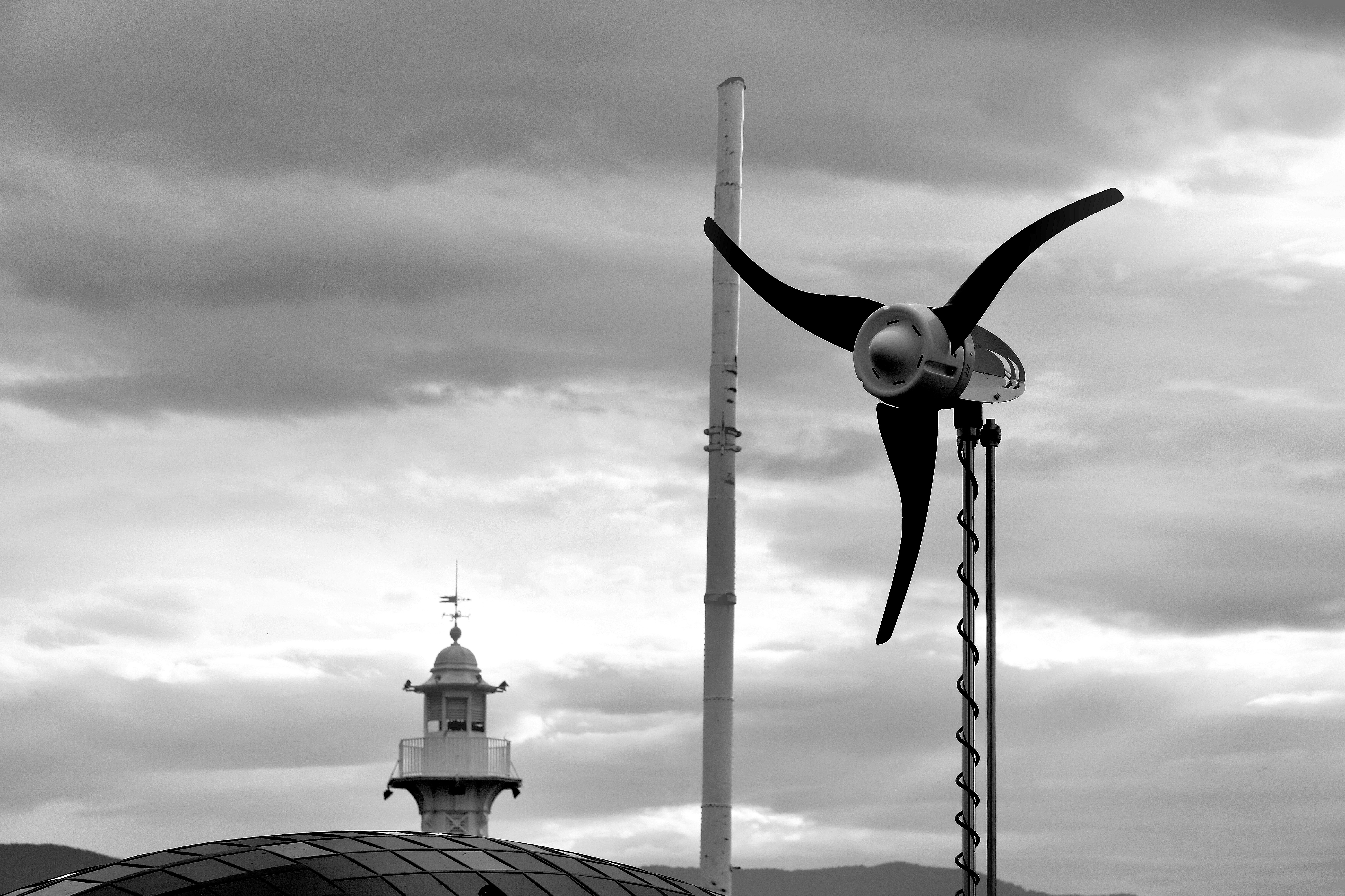 Wind turbine and lighthouse in front of cloudy sky