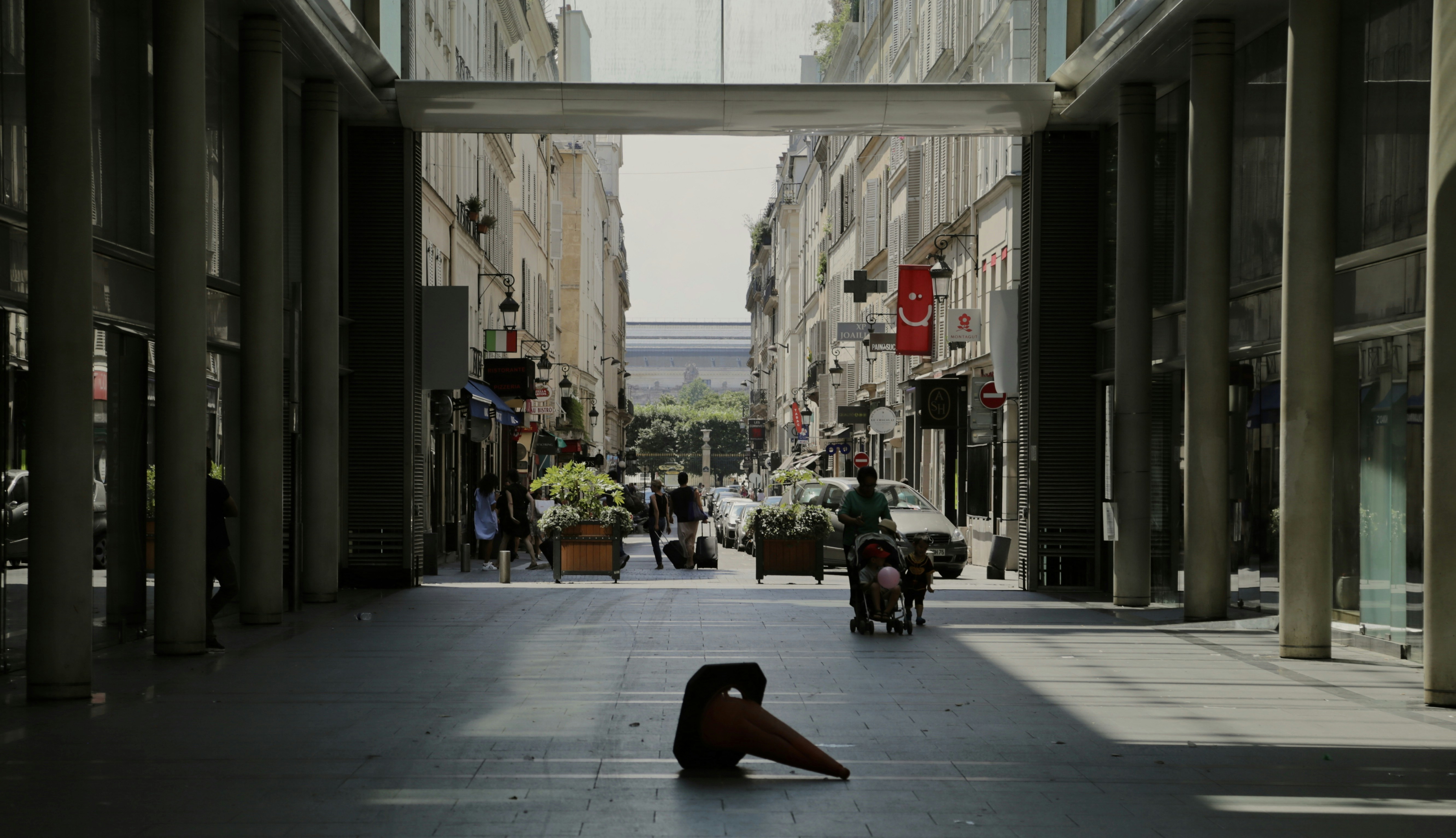 Orange Arc Anchors a Quiet City Street Under a Glass Canopy