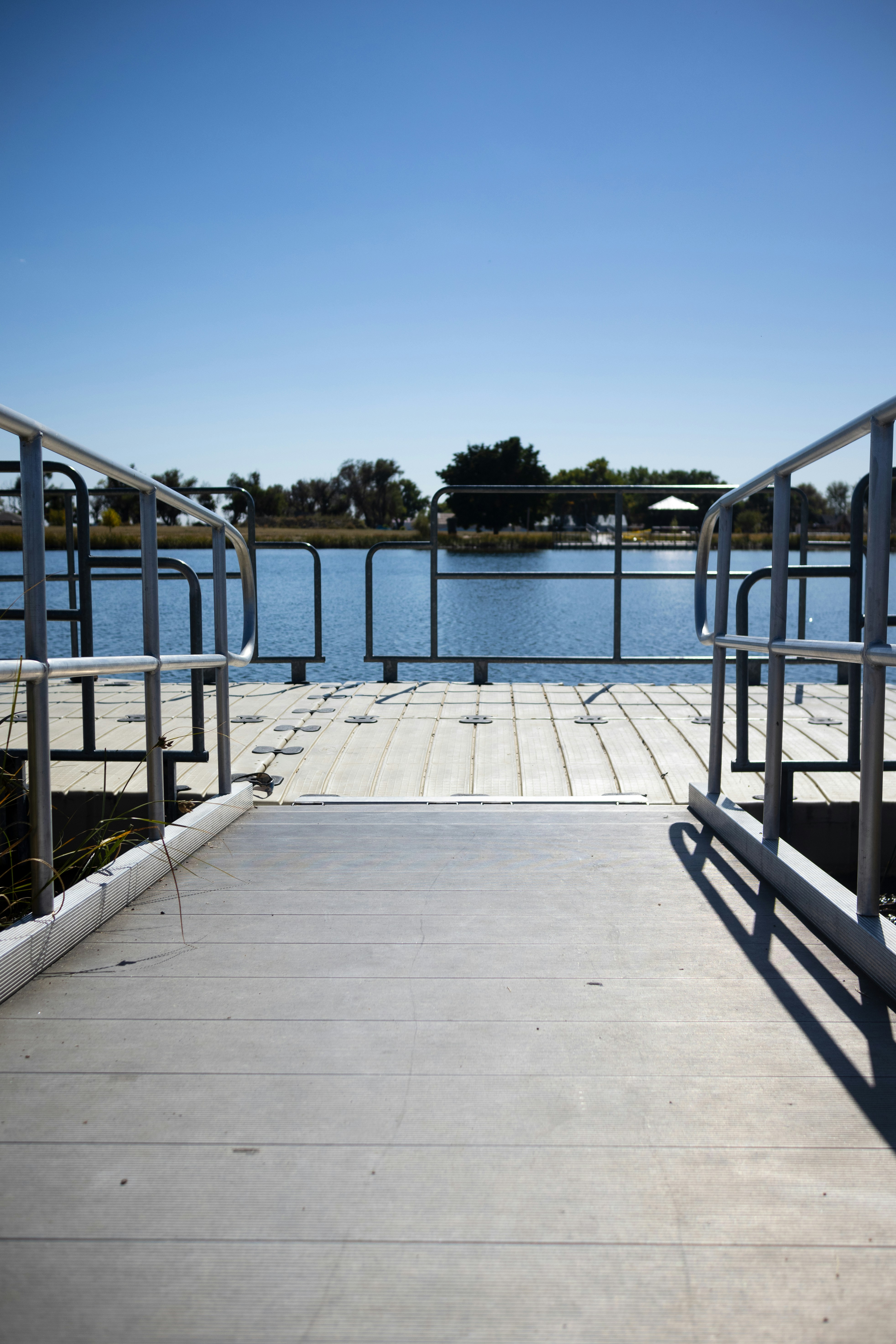 A wooden dock with metal railings next to a body of water photo – Free ...