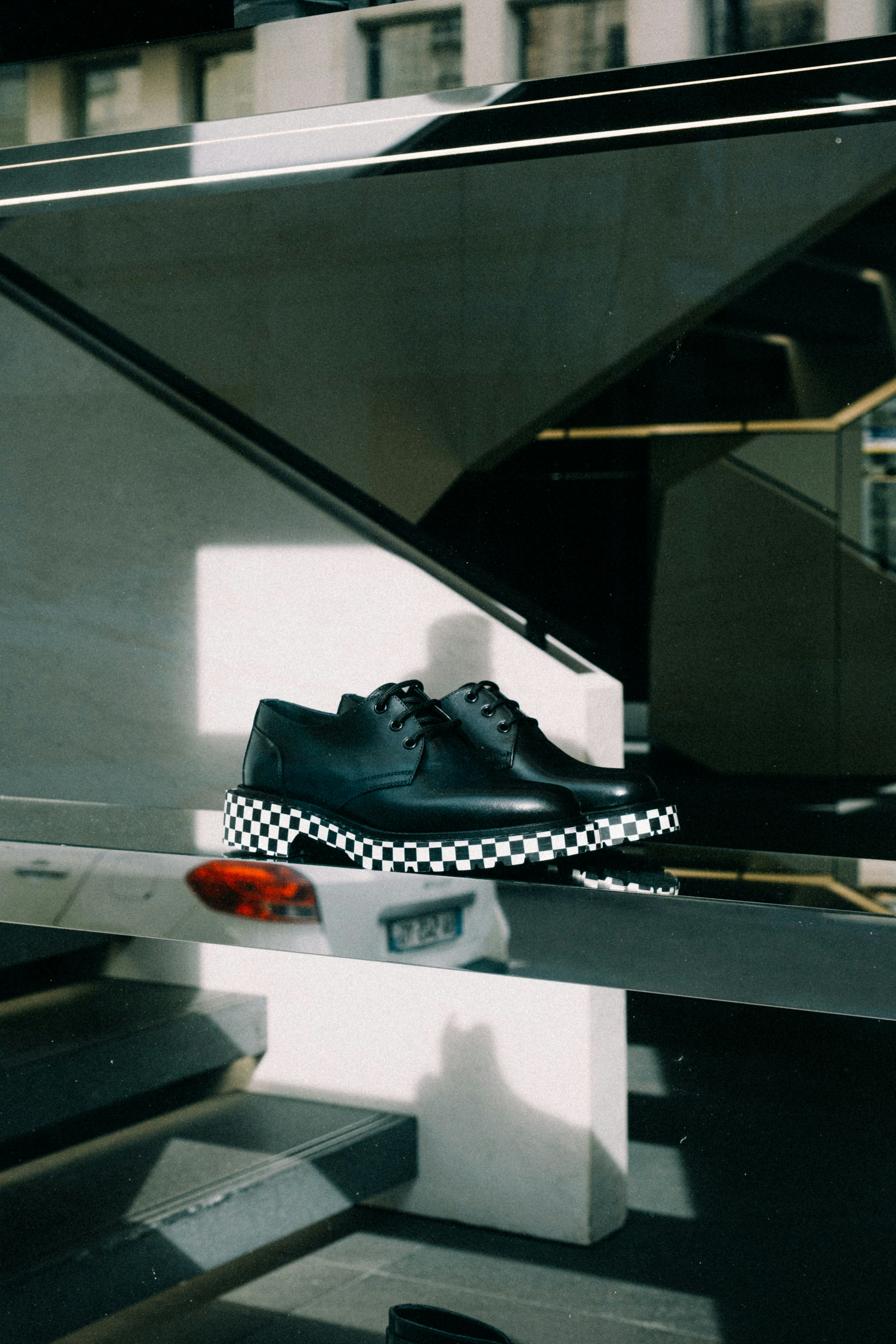 a pair of black shoes sitting on top of a metal rail