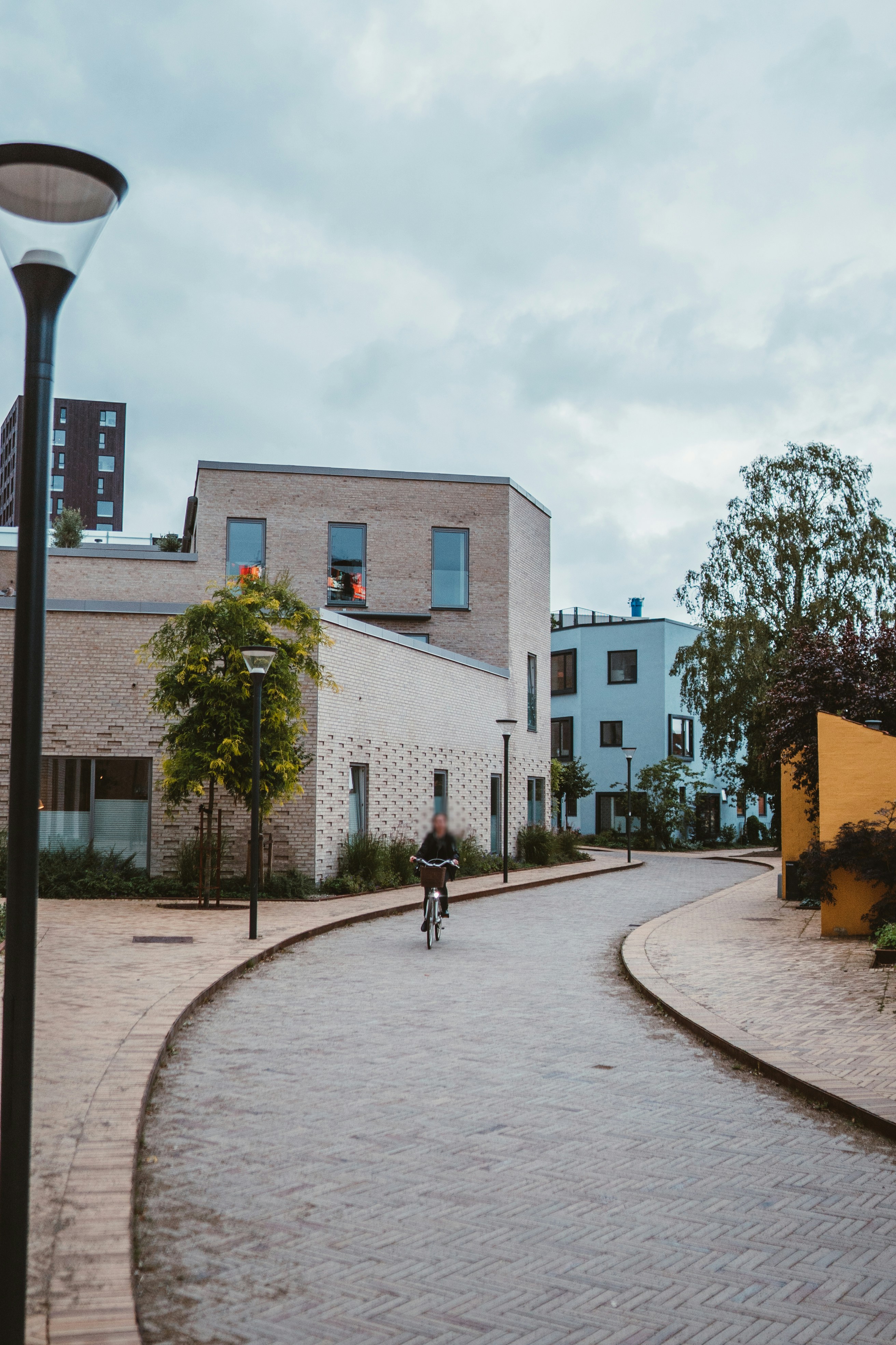 A person riding a bike down a cobblestone street photo – Free Odense ...