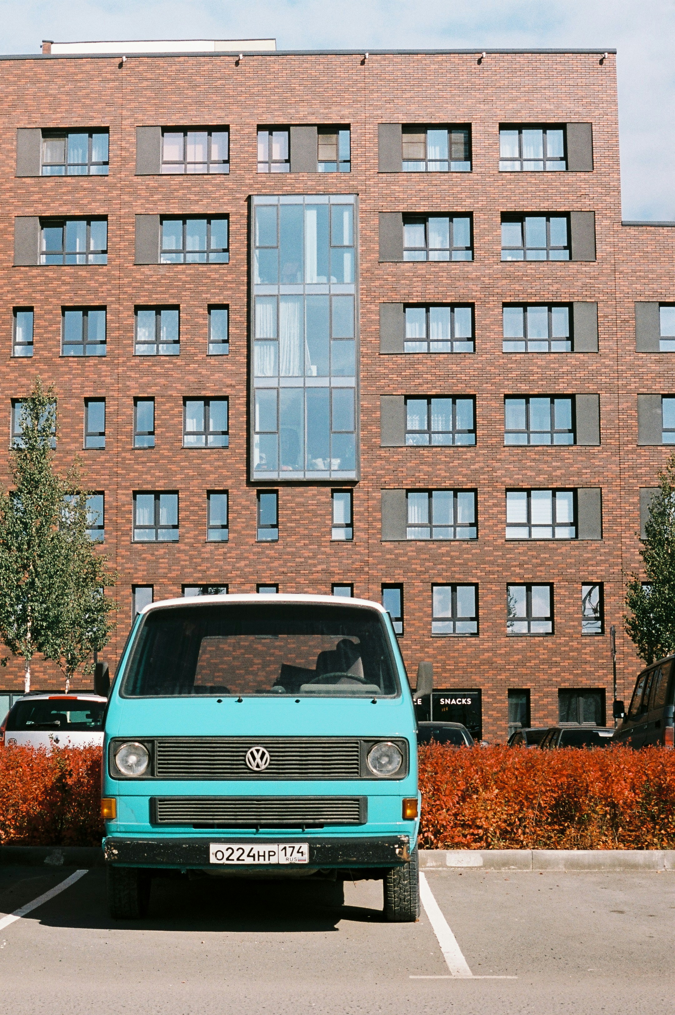 Turquoise van in front of brick dormitory under clear sky