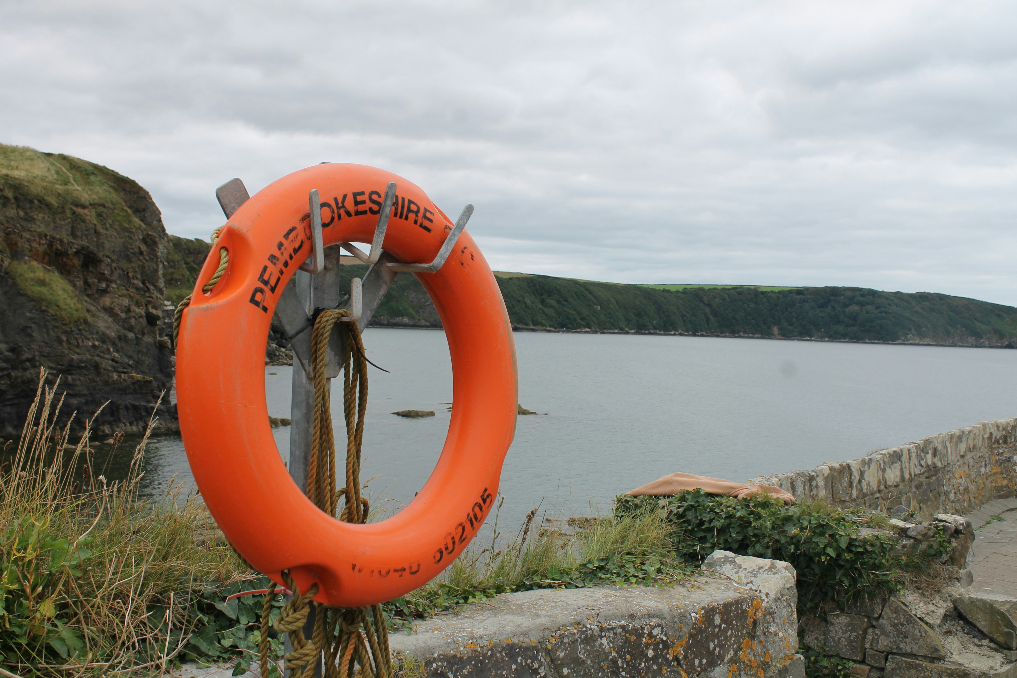 Lifebuoy on a Weathered Barrier Over a Quiet Cove
