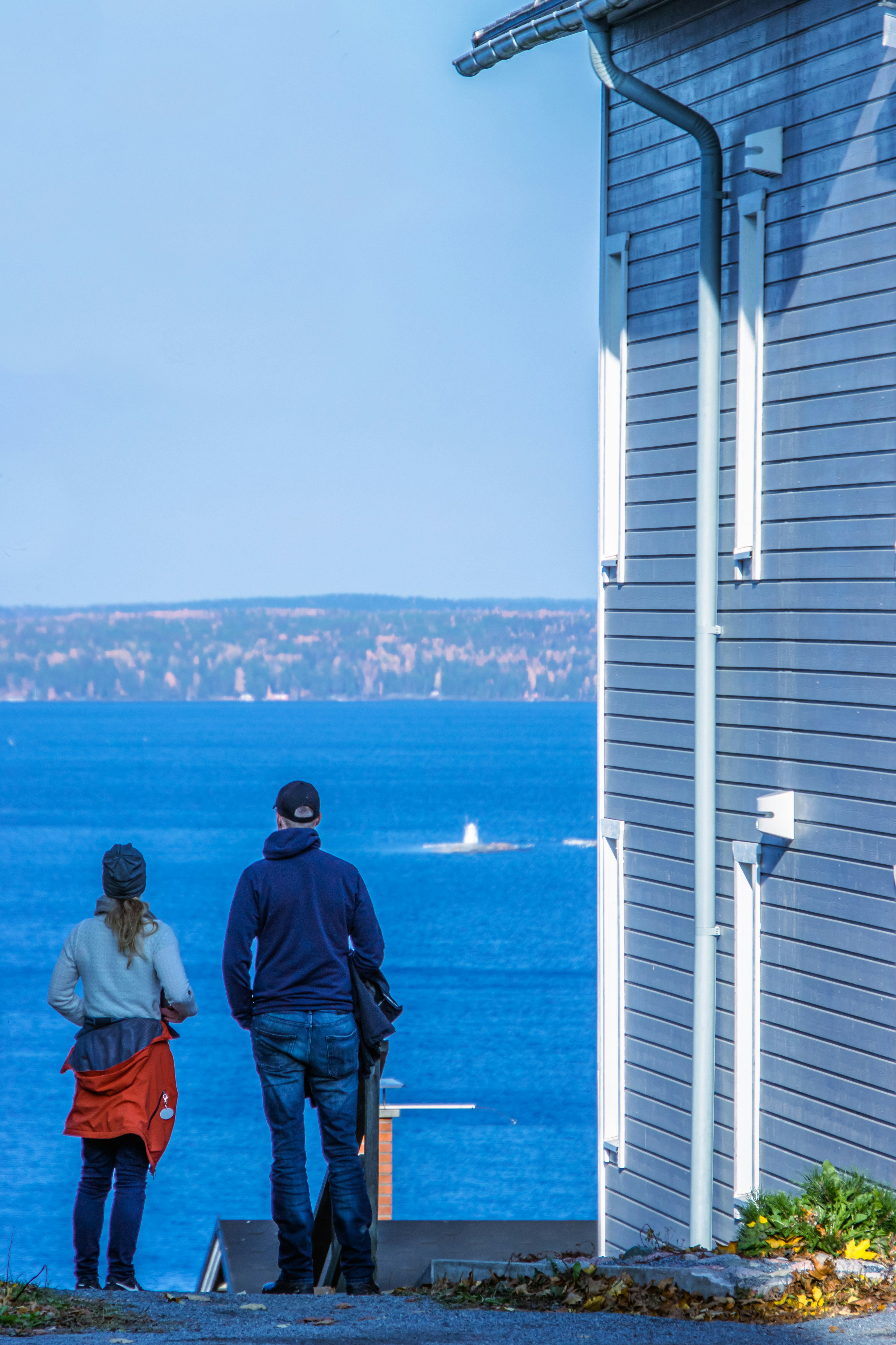 Two observers in blue against a sea-side bluehouse frame