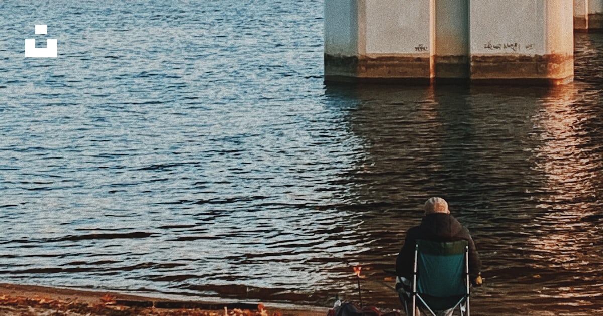 Foto Un Hombre Sentado En Una Playa Junto A Un Cuerpo De Agua Imagen