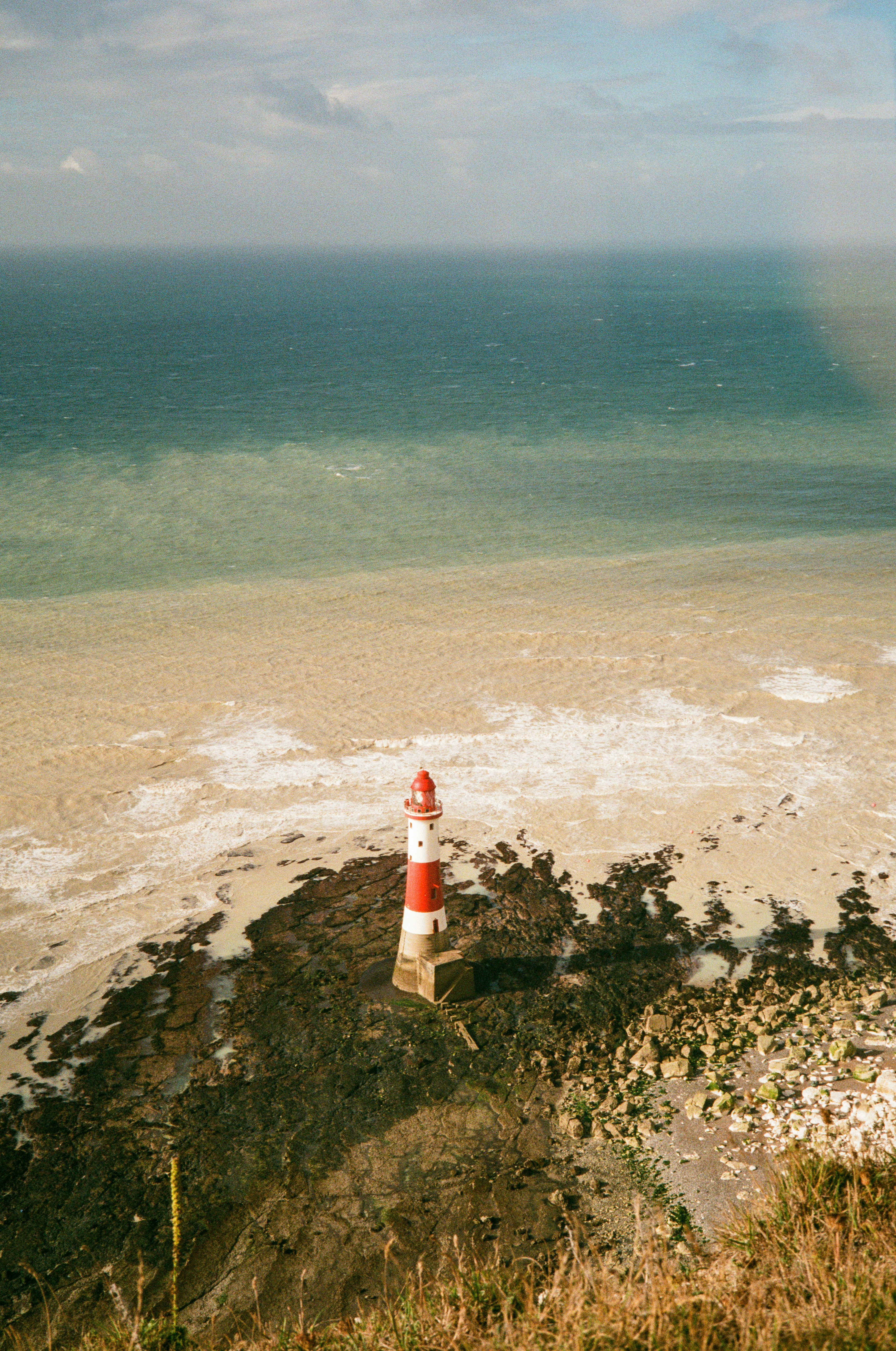 Beacon on Basalt Shore: Red-and-White Lighthouse Beside Turquoise Tide