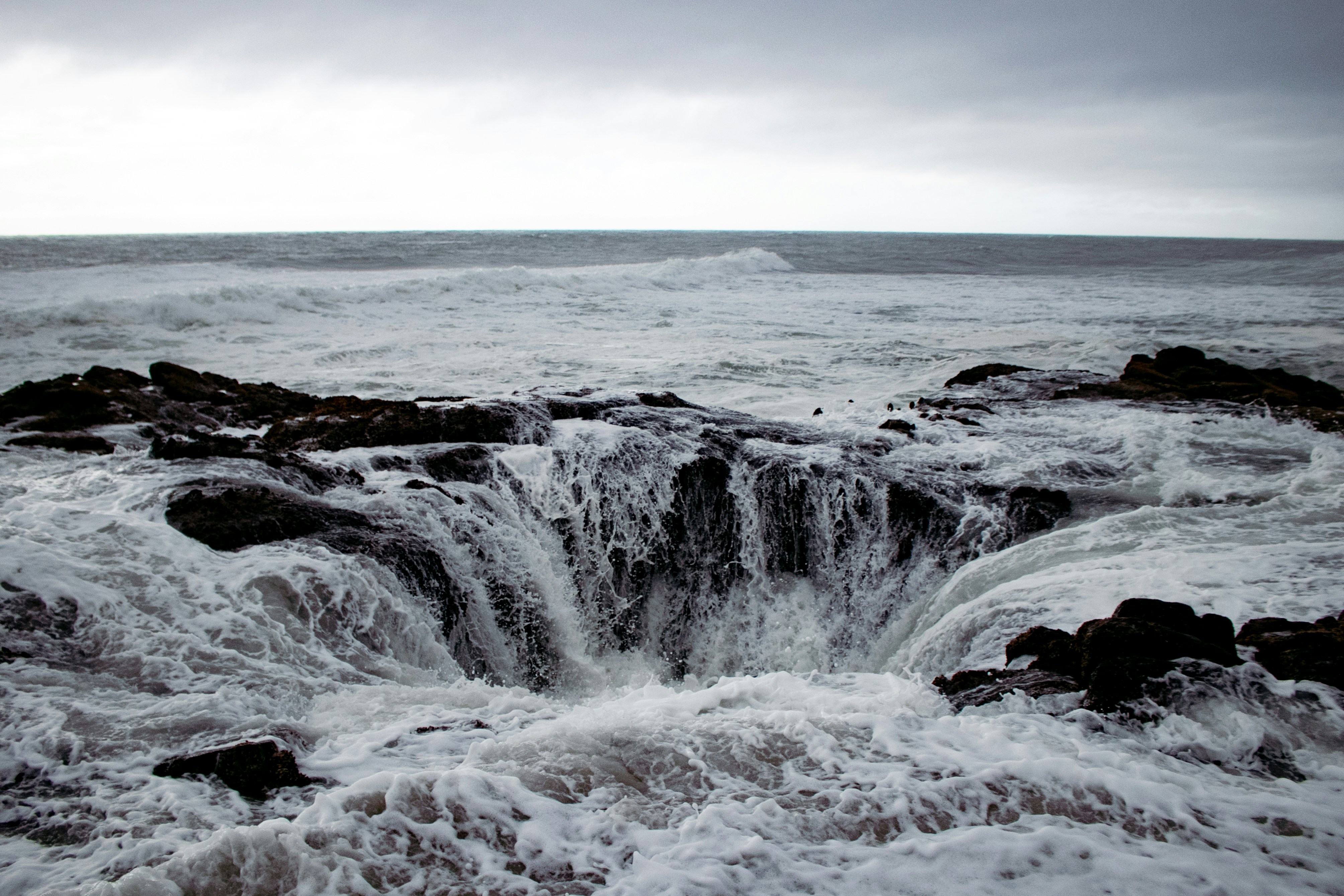 A large body of water surrounded by rocks photo – Free Ocean Image on ...