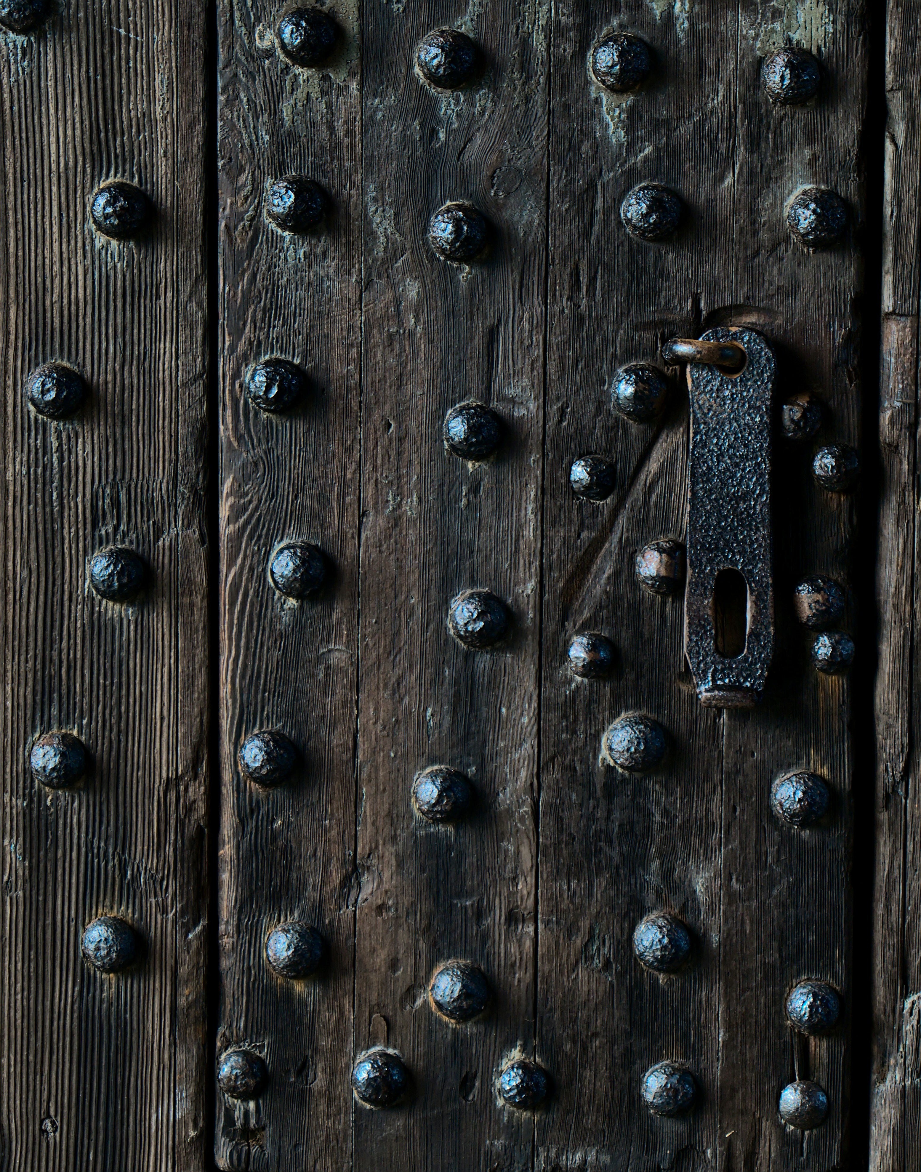 Close-up of a wooden door with iron studs and a metal latch.