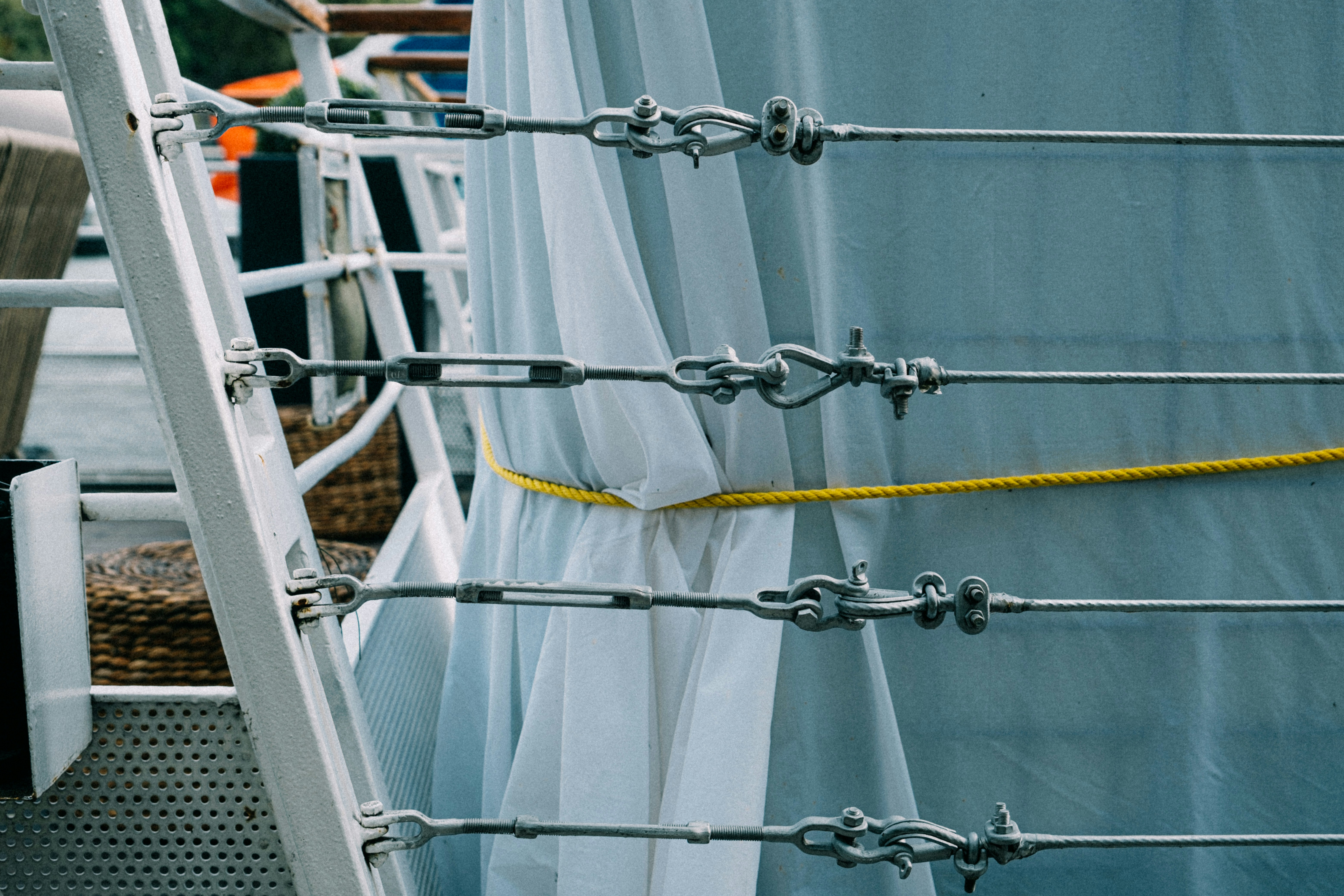 Close-up of metal rigging and a draped fabric on a boat, highlighting the interplay of materials and maritime elements.