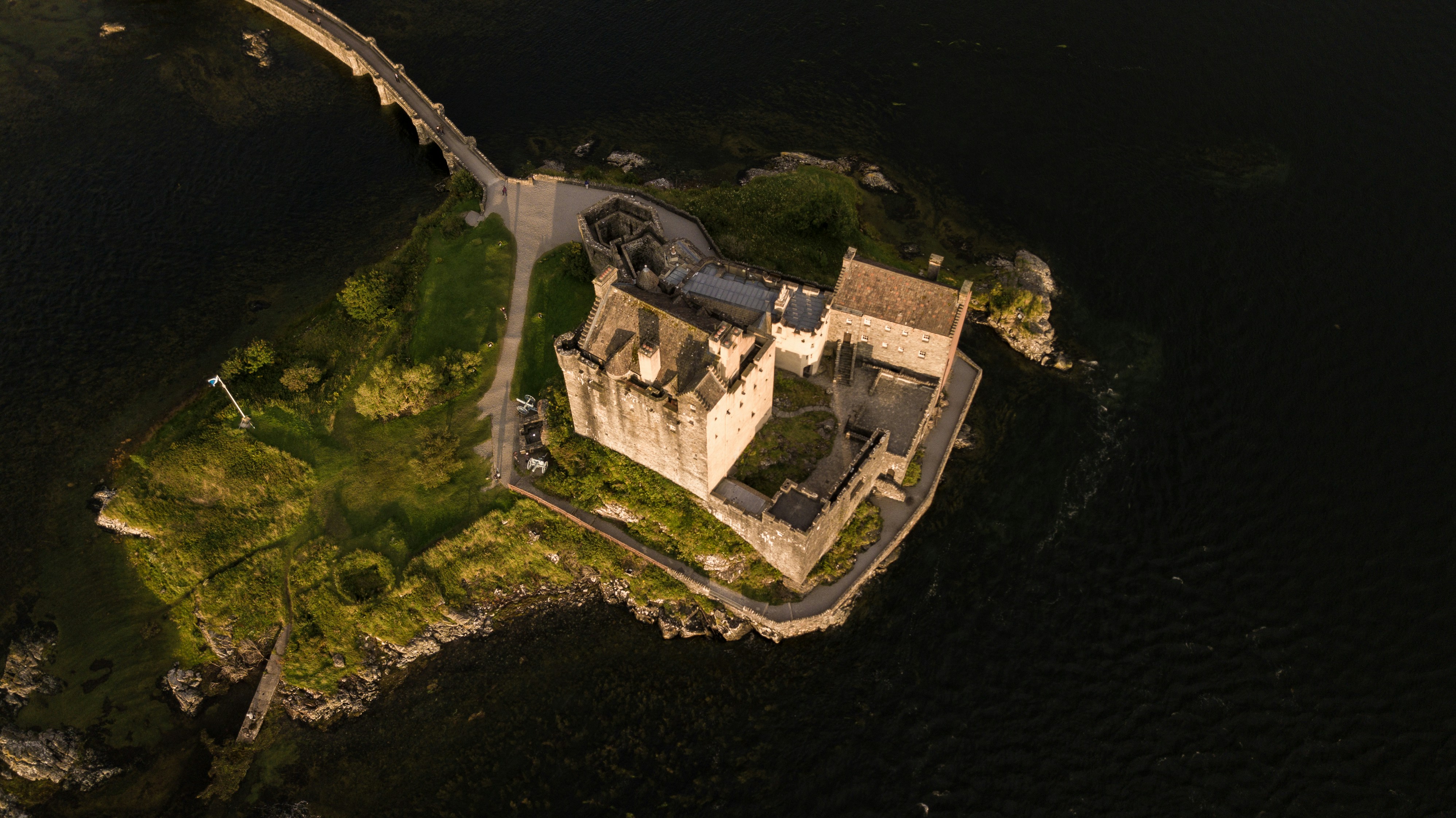 Historic castle perched on a rocky isle, surrounded by shimmering waters and lush greenery.