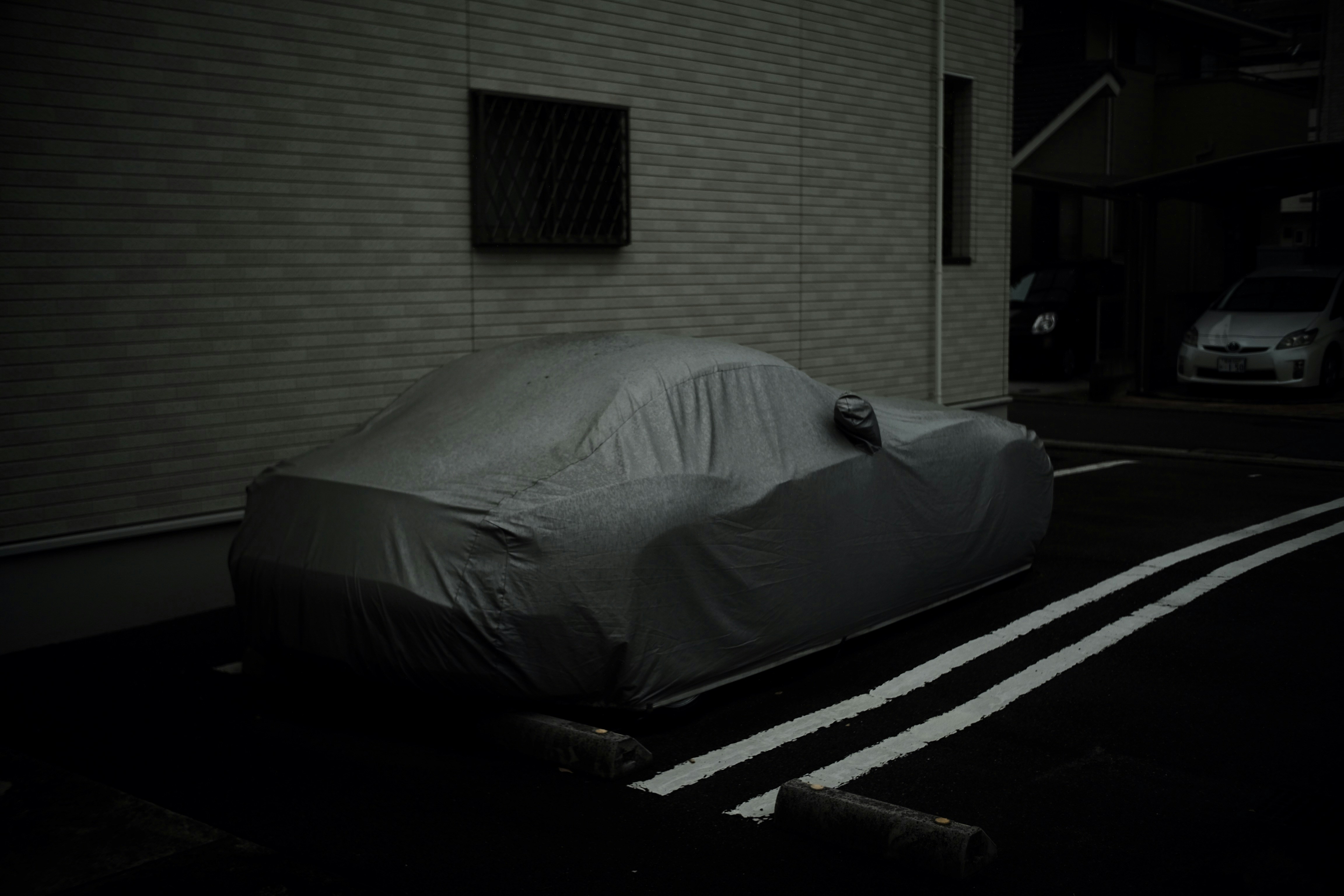 Veiled Sedan in a Shadowed Parking Lot