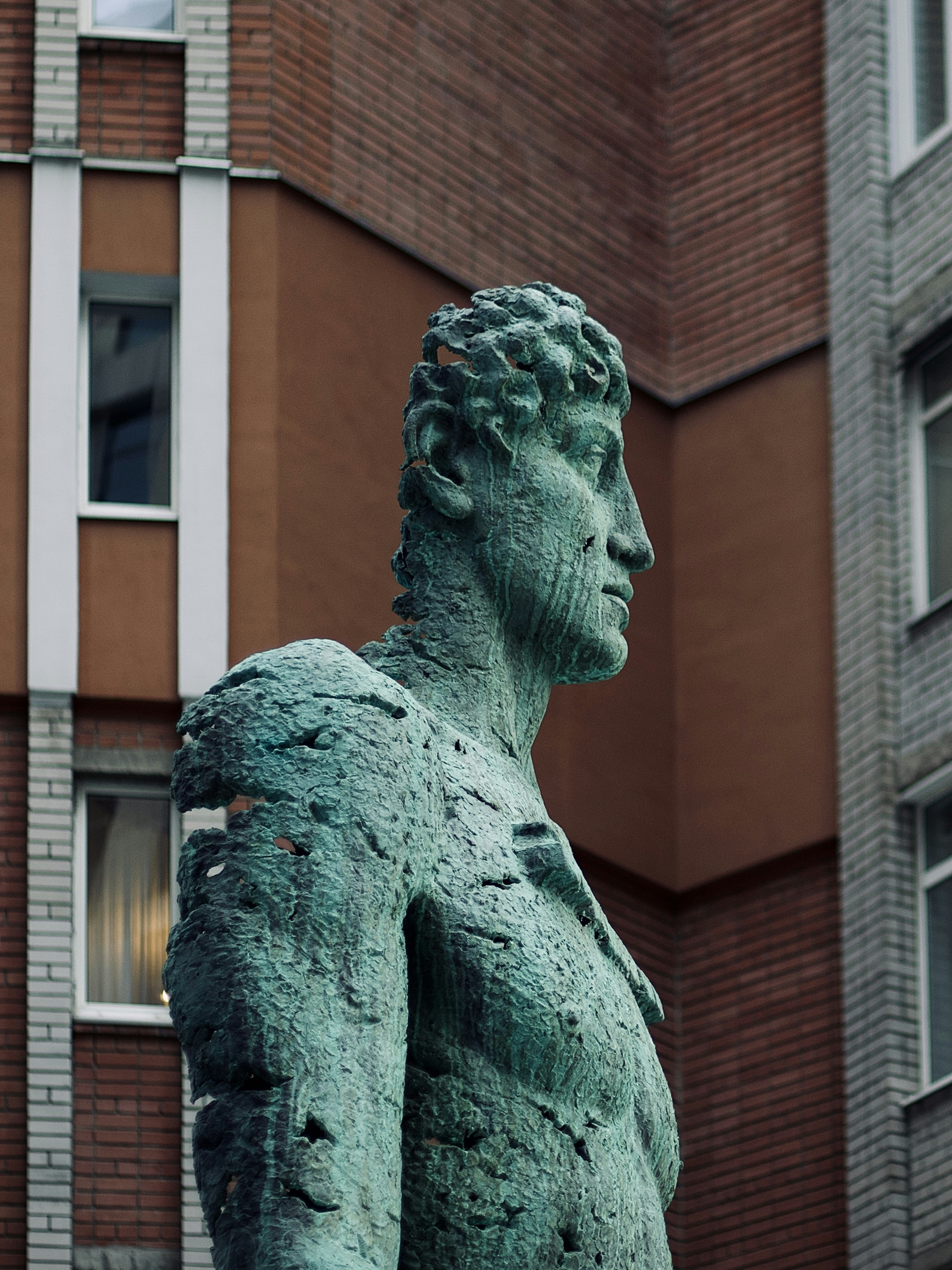 Bronze Figure in Copper Patina Against Urban Brick