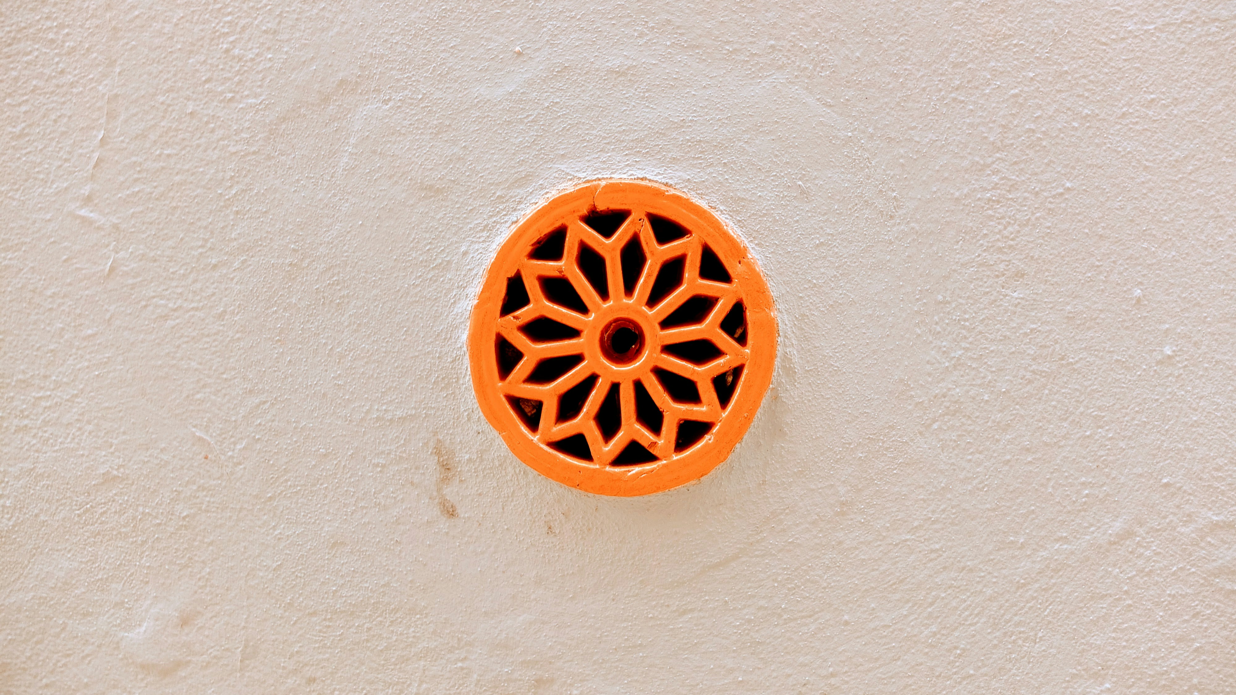 A round orange object on a white wall photo – Free Architecture Image ...