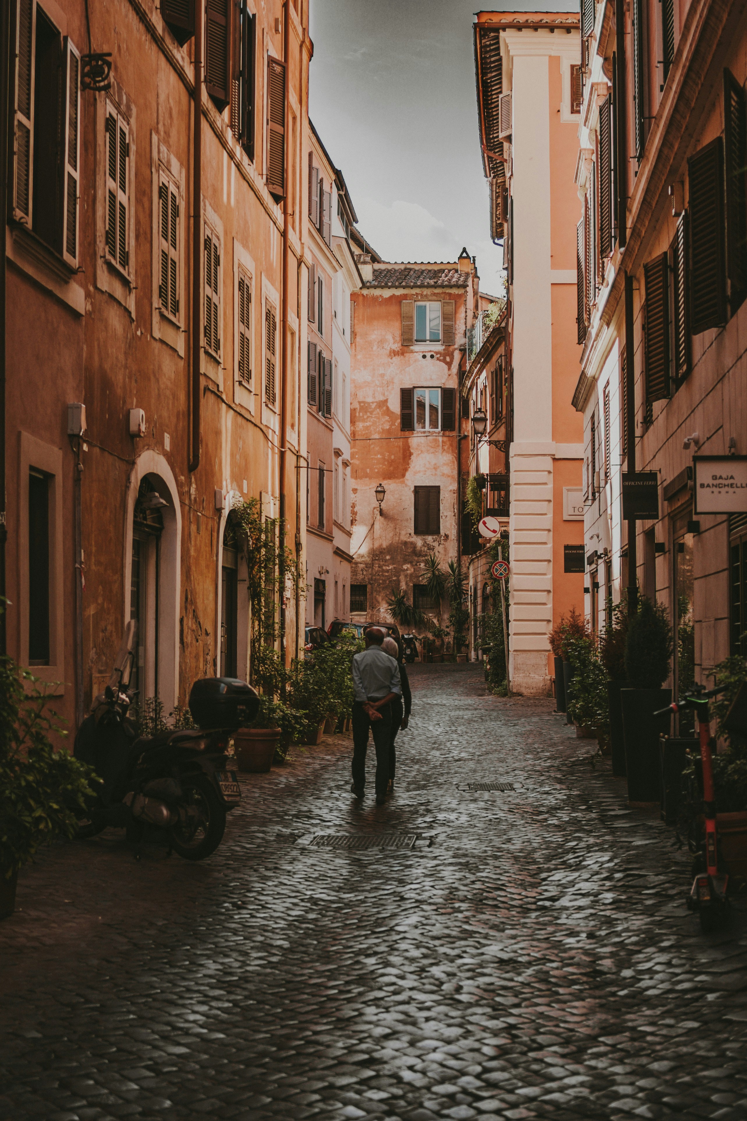 Cobbled Corridor of Warmth: A Lone Wanderer Beneath Terracotta Facades