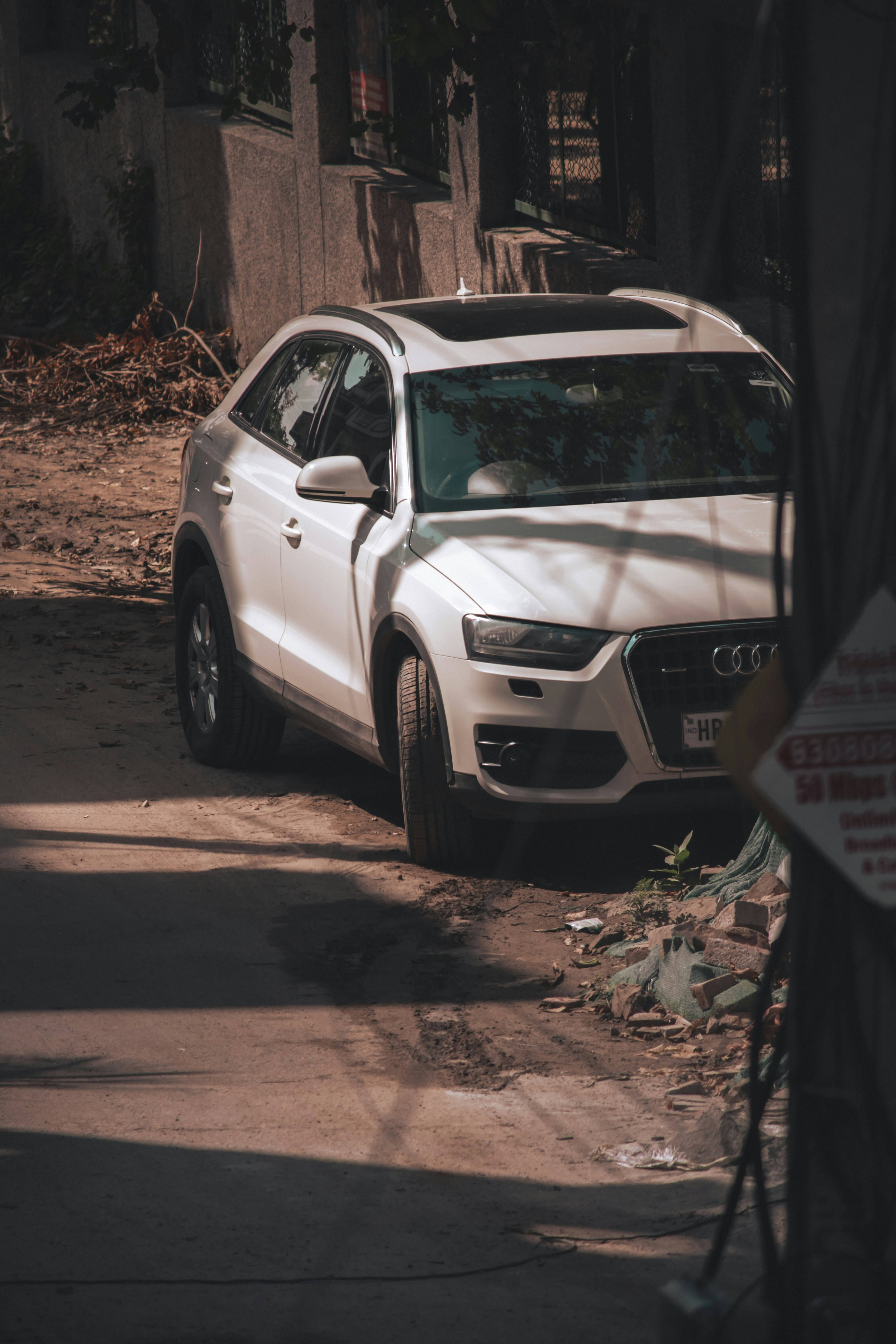 A sleek white Audi parked on a sunlit street, surrounded by urban textures and shadows.