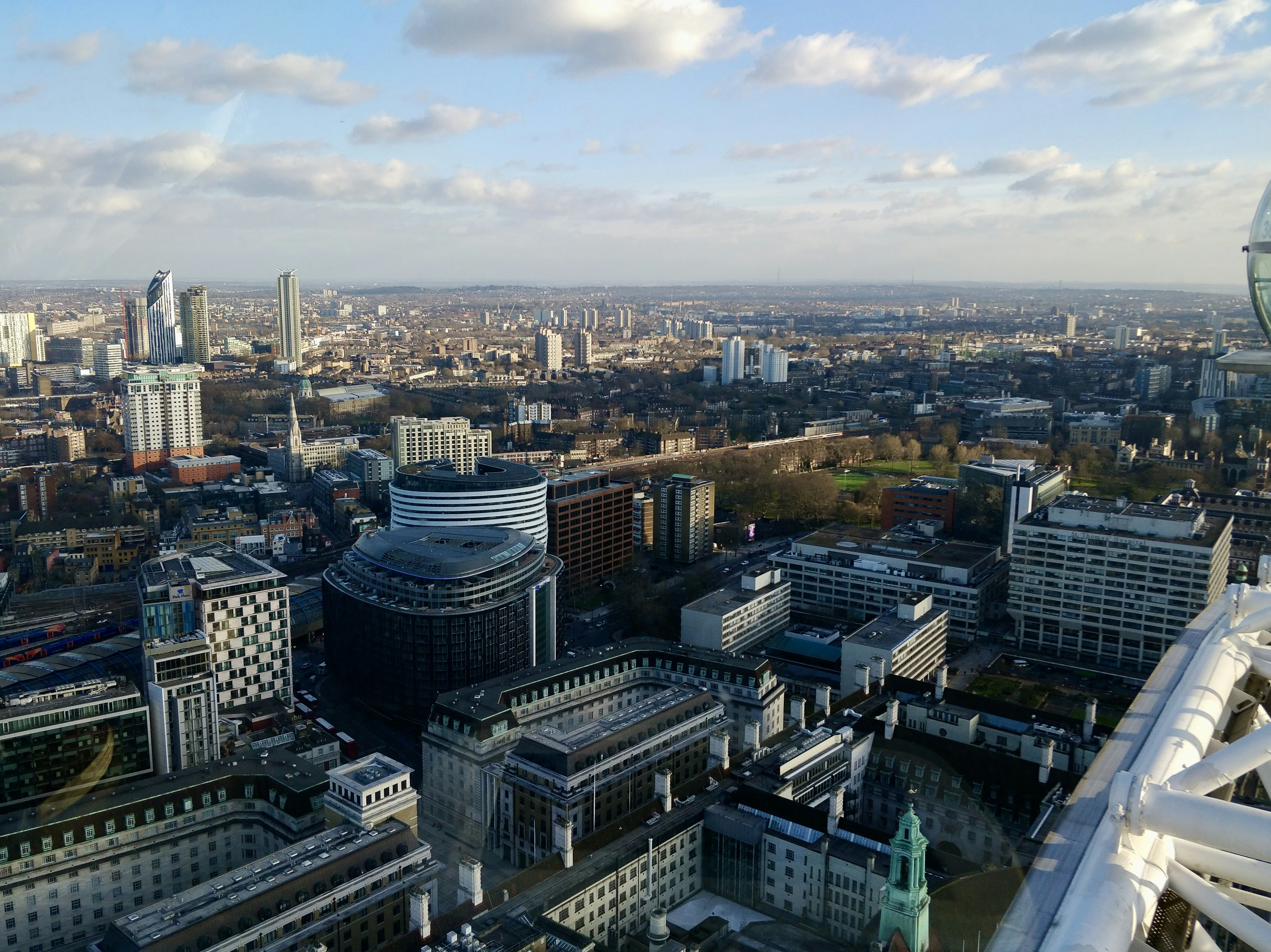 Aerial view of London's cityscape showcasing a blend of modern architecture and historical buildings under a partly cloudy sky.
