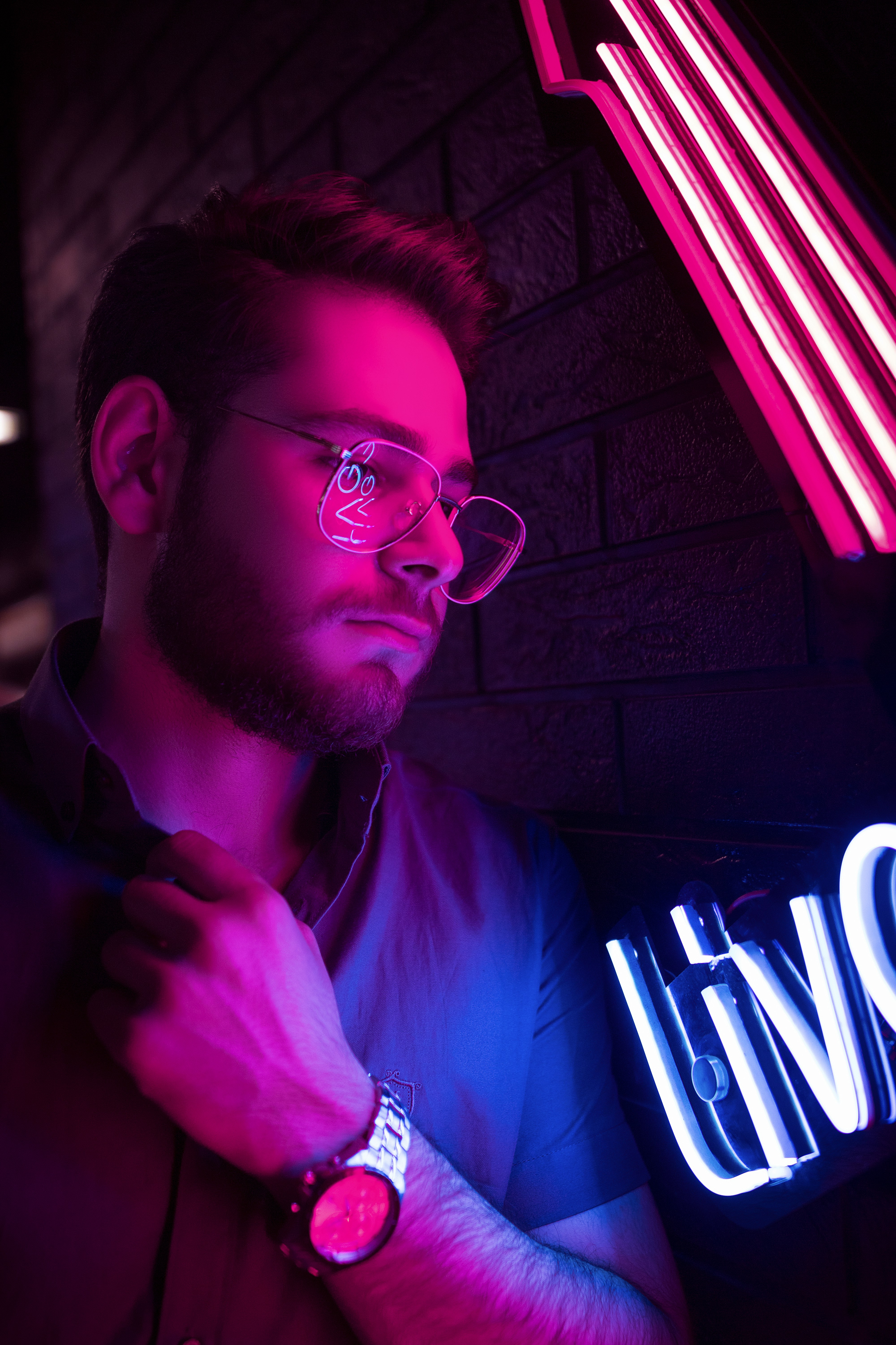 A man wearing glasses standing in front of a neon sign photo – Free ...