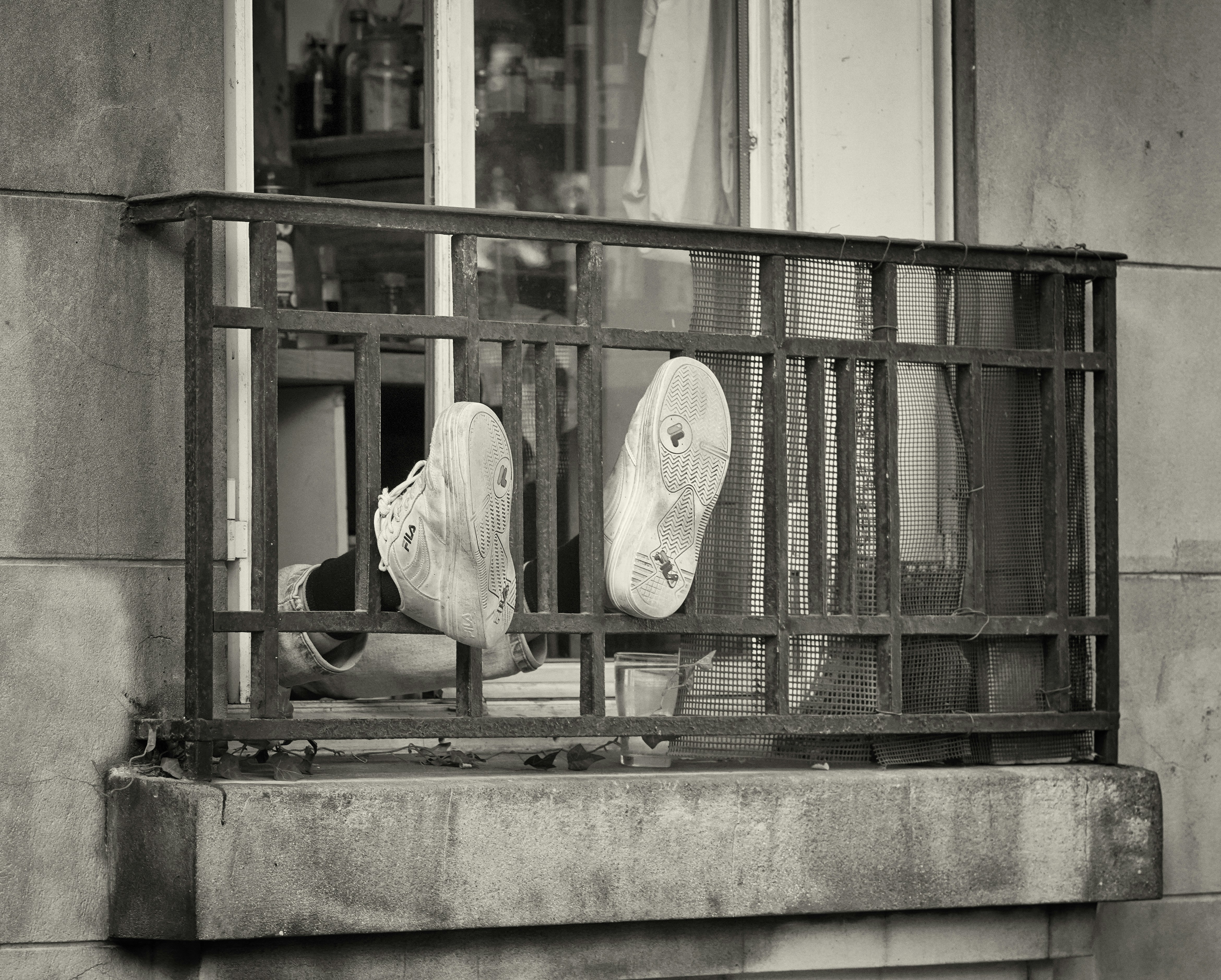 Monochrome Pause: Sneakers Rest on a Weathered Balcony Railing