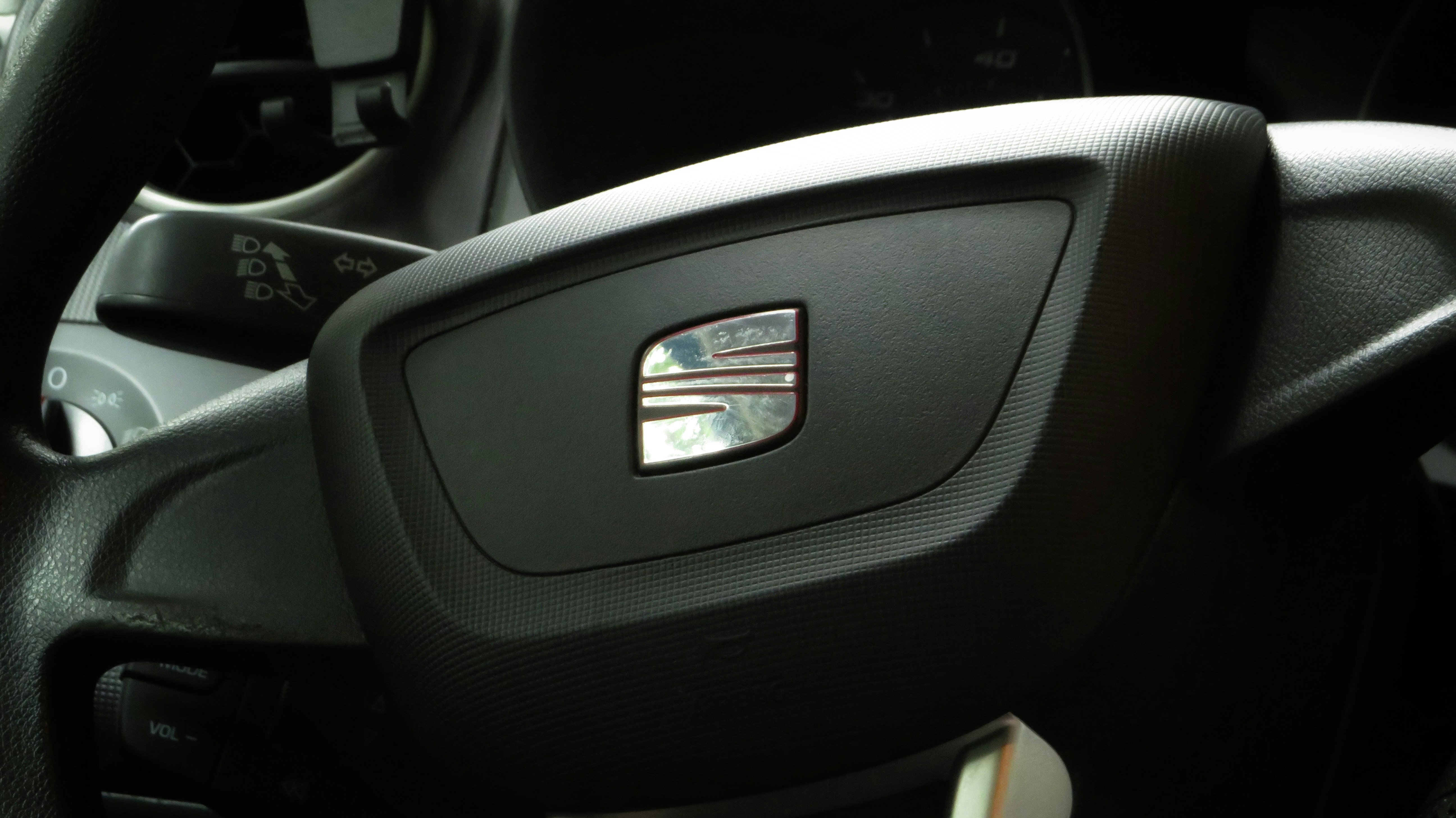 Close-up of a car steering wheel featuring the logo of a well-known automobile brand, showcasing the texture and details of the interior design.