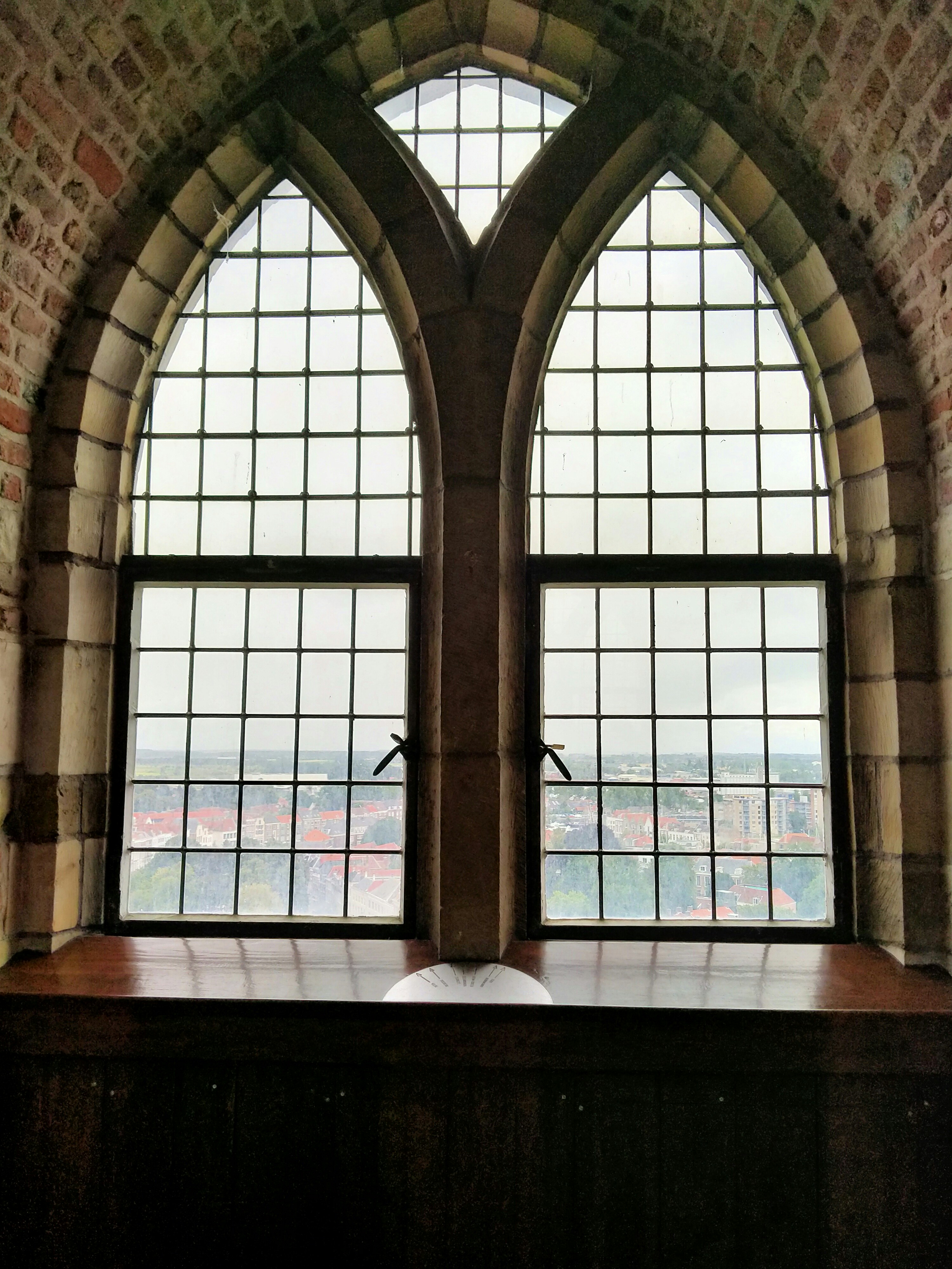 Pastoral Vantage: Arched Window Framing a Cityscape