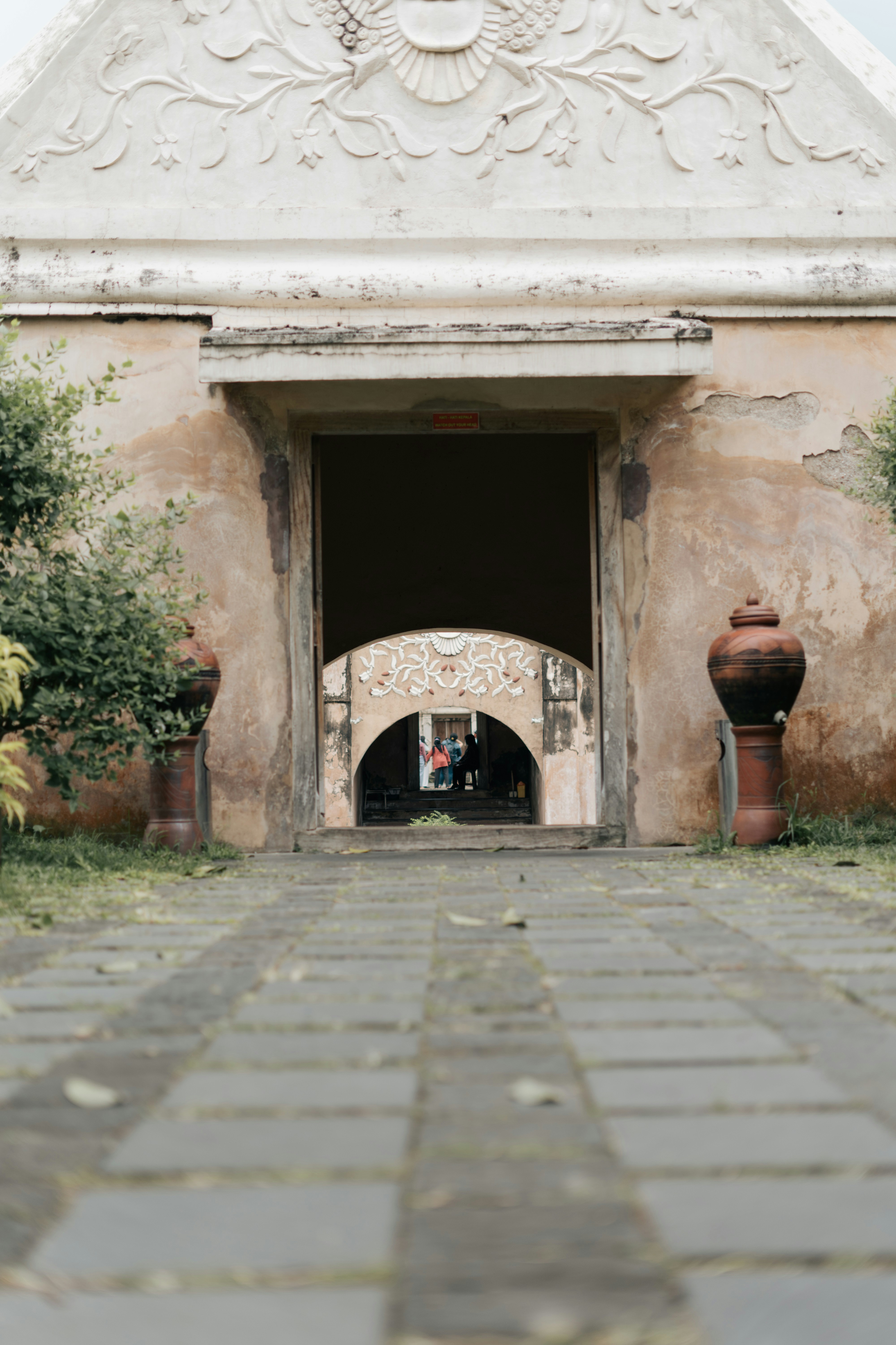 Intricate archway framed by lush greenery, leading into a historic structure with weathered walls. The scene invites exploration and discovery.