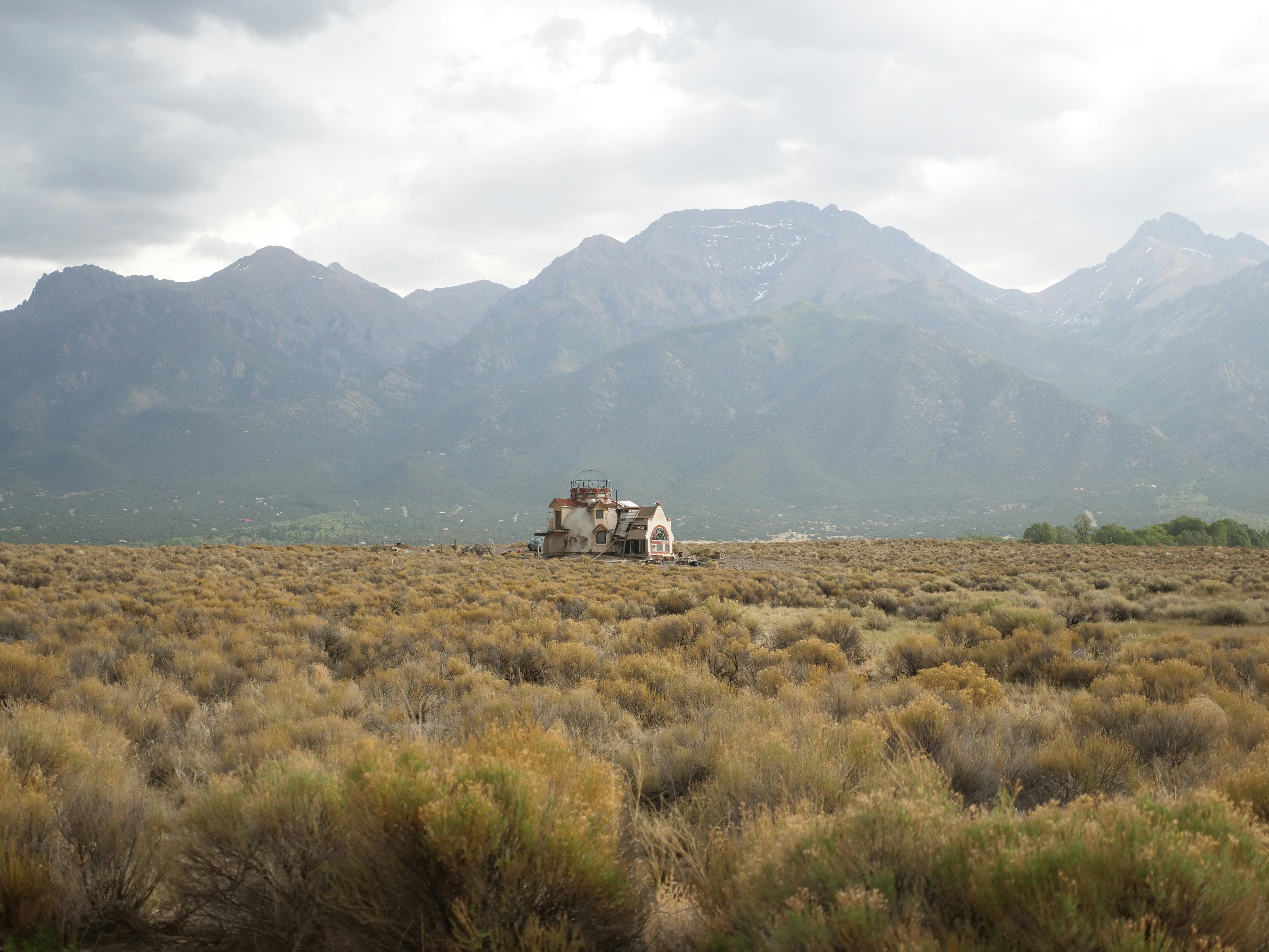 A house in the middle of a field with mountains in the background photo ...