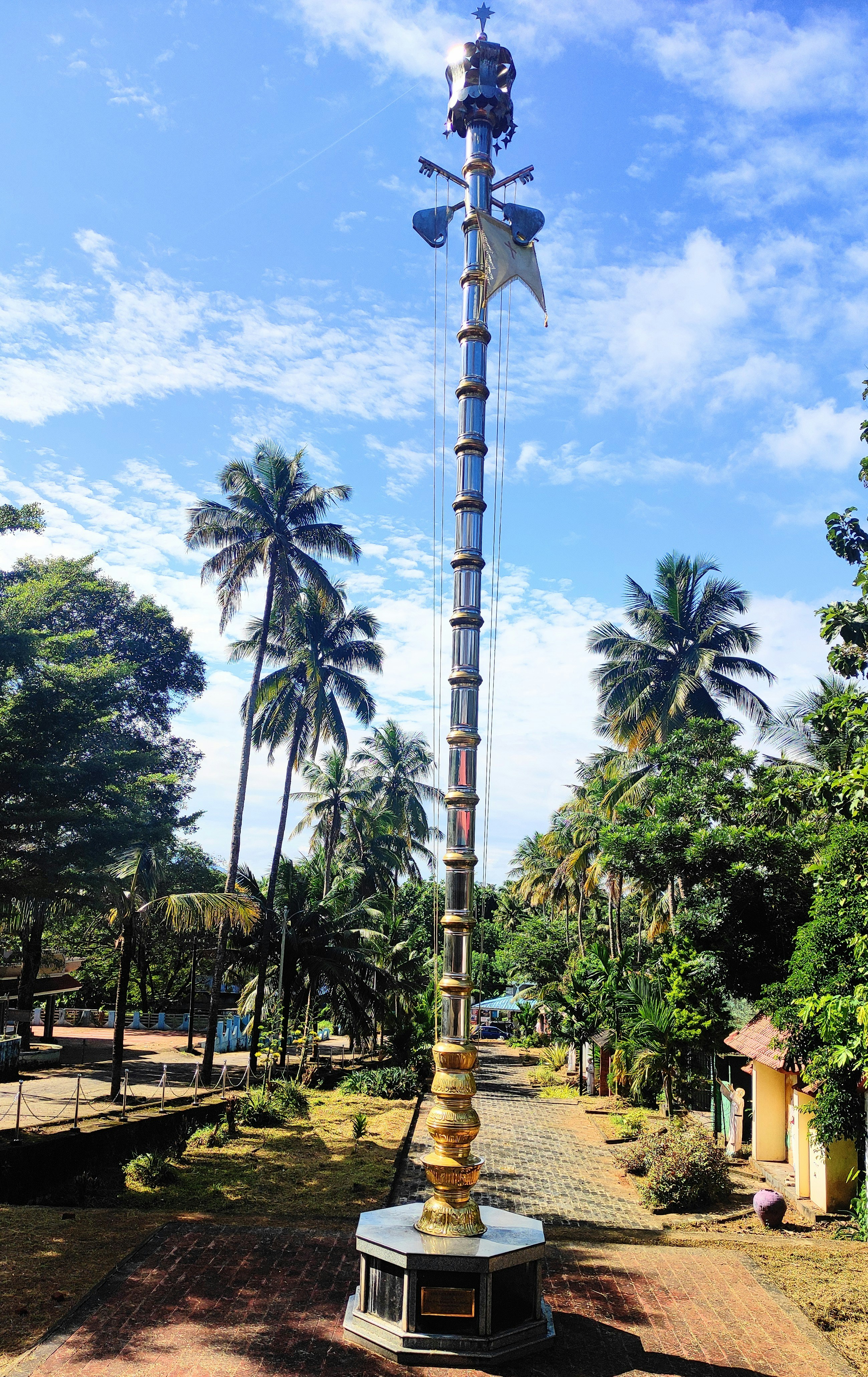 A towering temple lamp stands amidst palm trees, symbolizing cultural heritage and spirituality in a serene landscape.