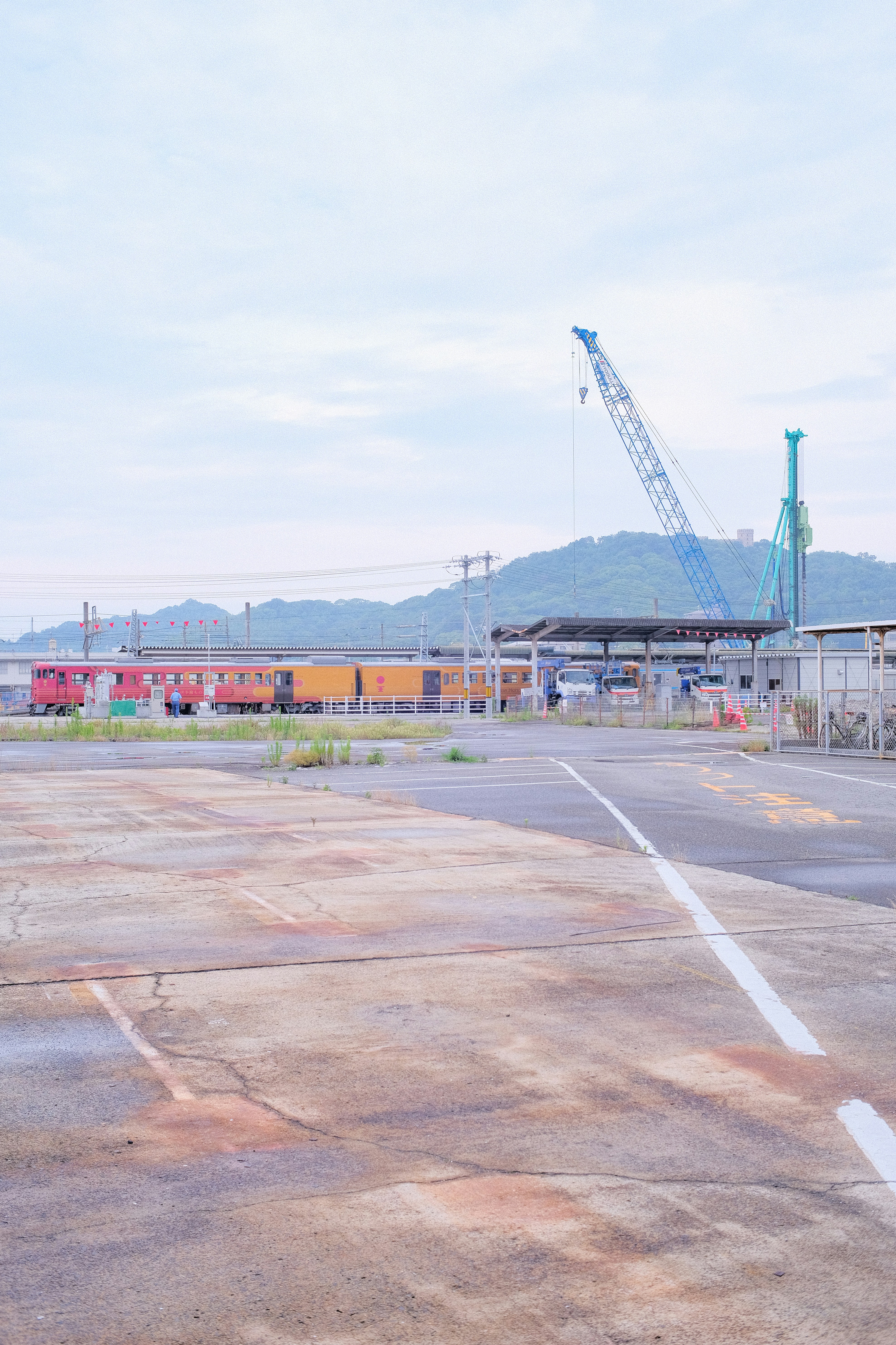 an empty parking lot with a crane in the background