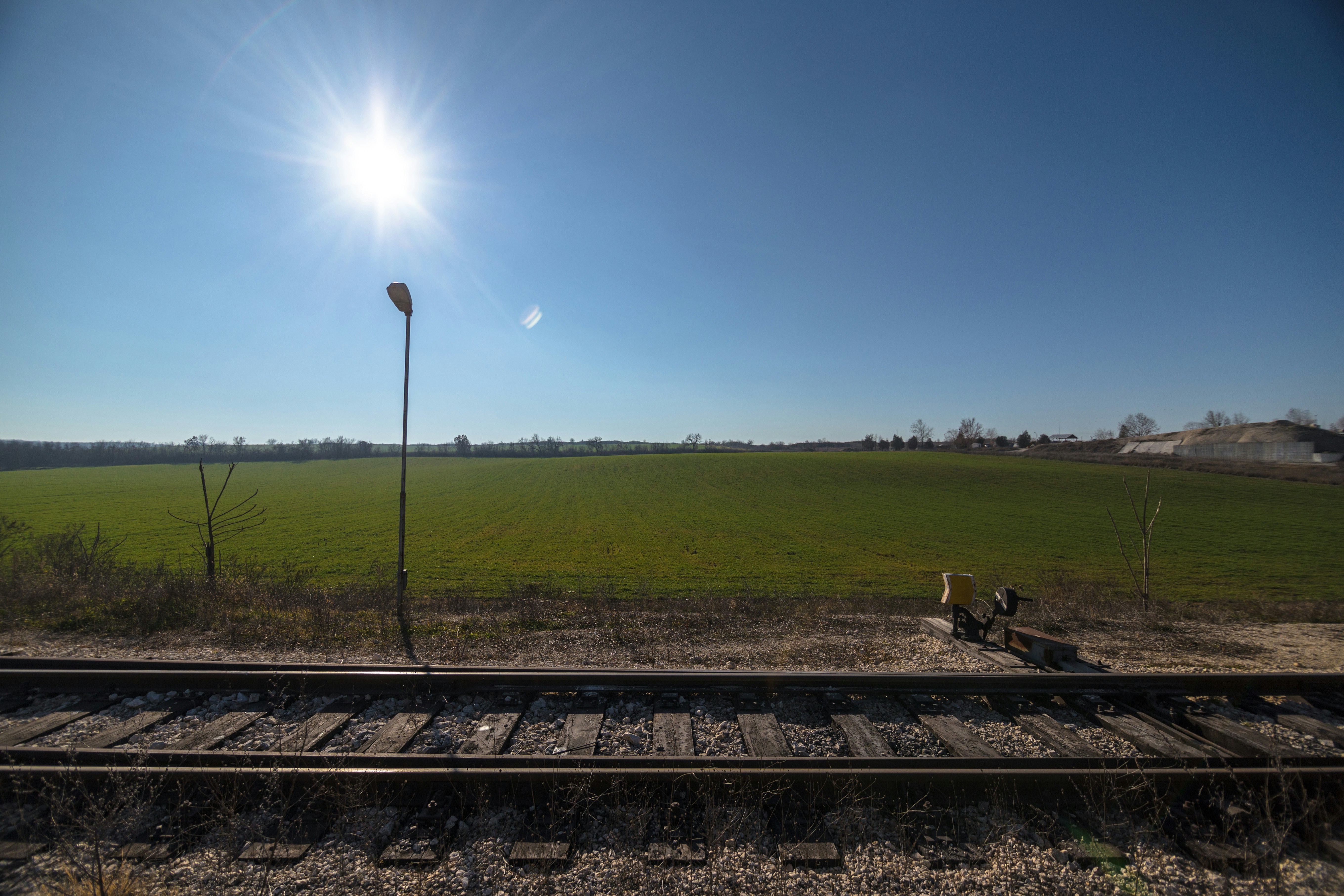 Sunlit Rails and the Quiet Horizon: A Lone Lamppost Anchors the Field
