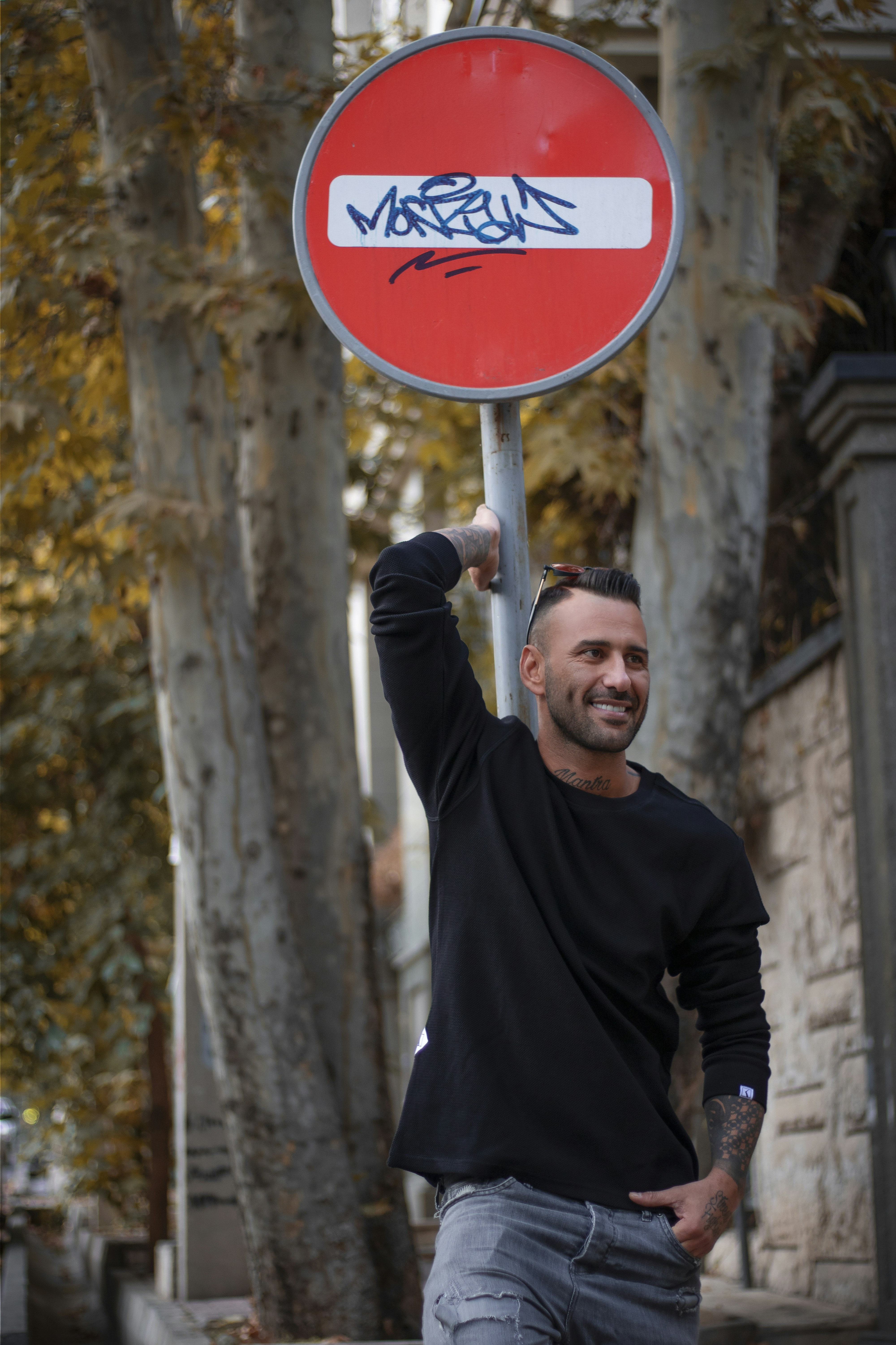 Autumn Street Portrait: Man Pausing by a Graffiti-Streaked No-Entry Sign