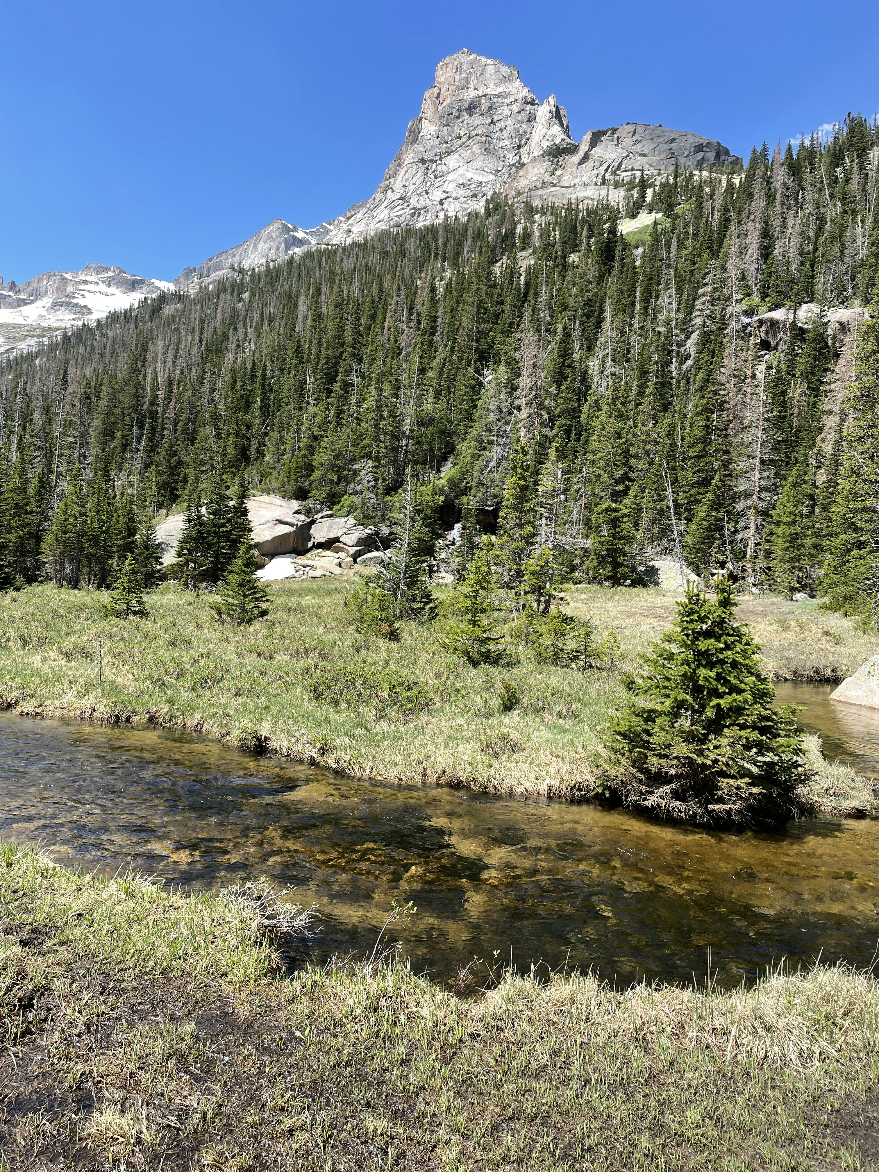 Granite Sentinel Over a Quiet Alpine Creek Under a Clear Sky