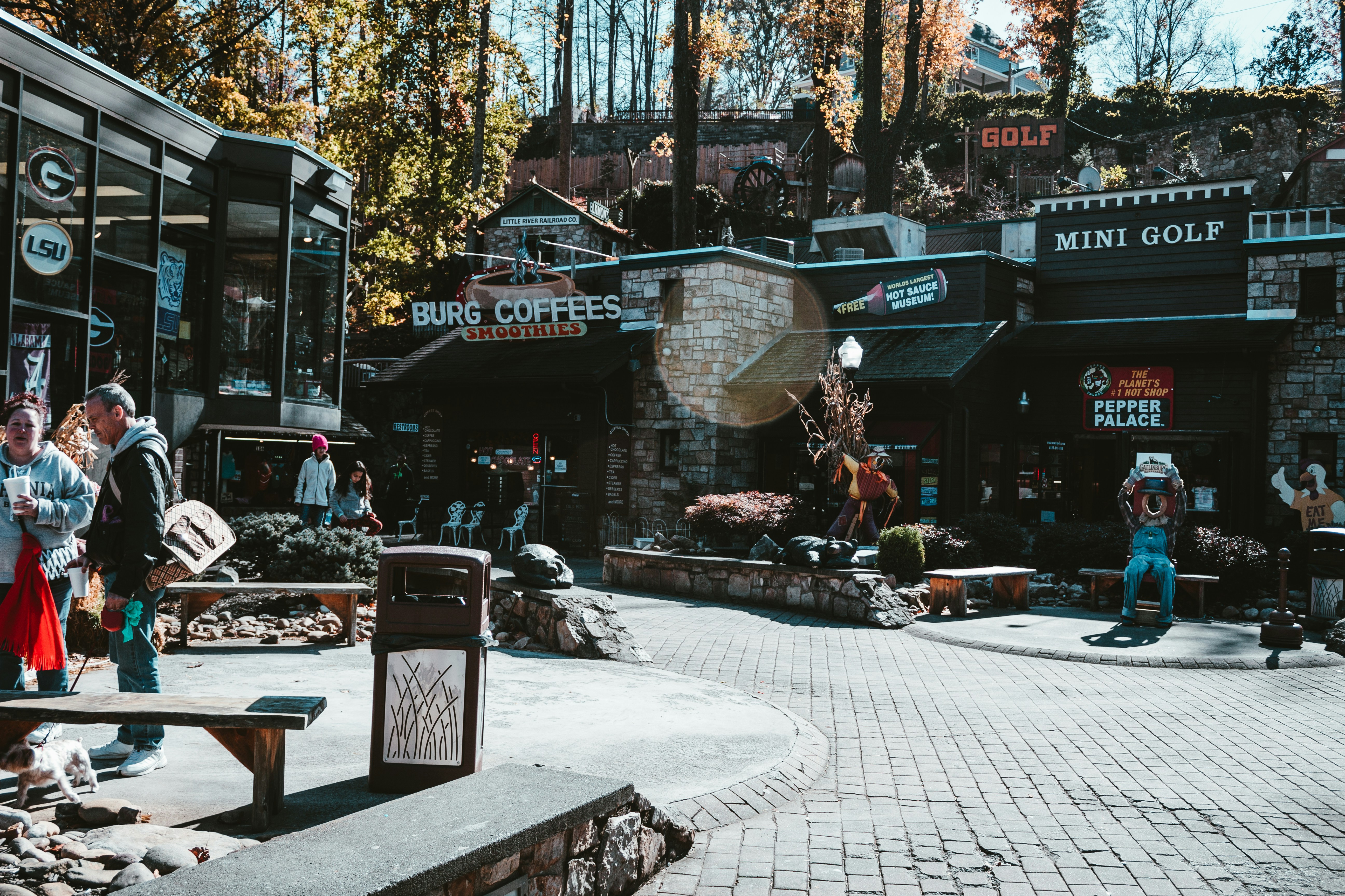 A vibrant outdoor plaza filled with shops and visitors enjoying leisure activities. The scene features a mix of dining and entertainment options.