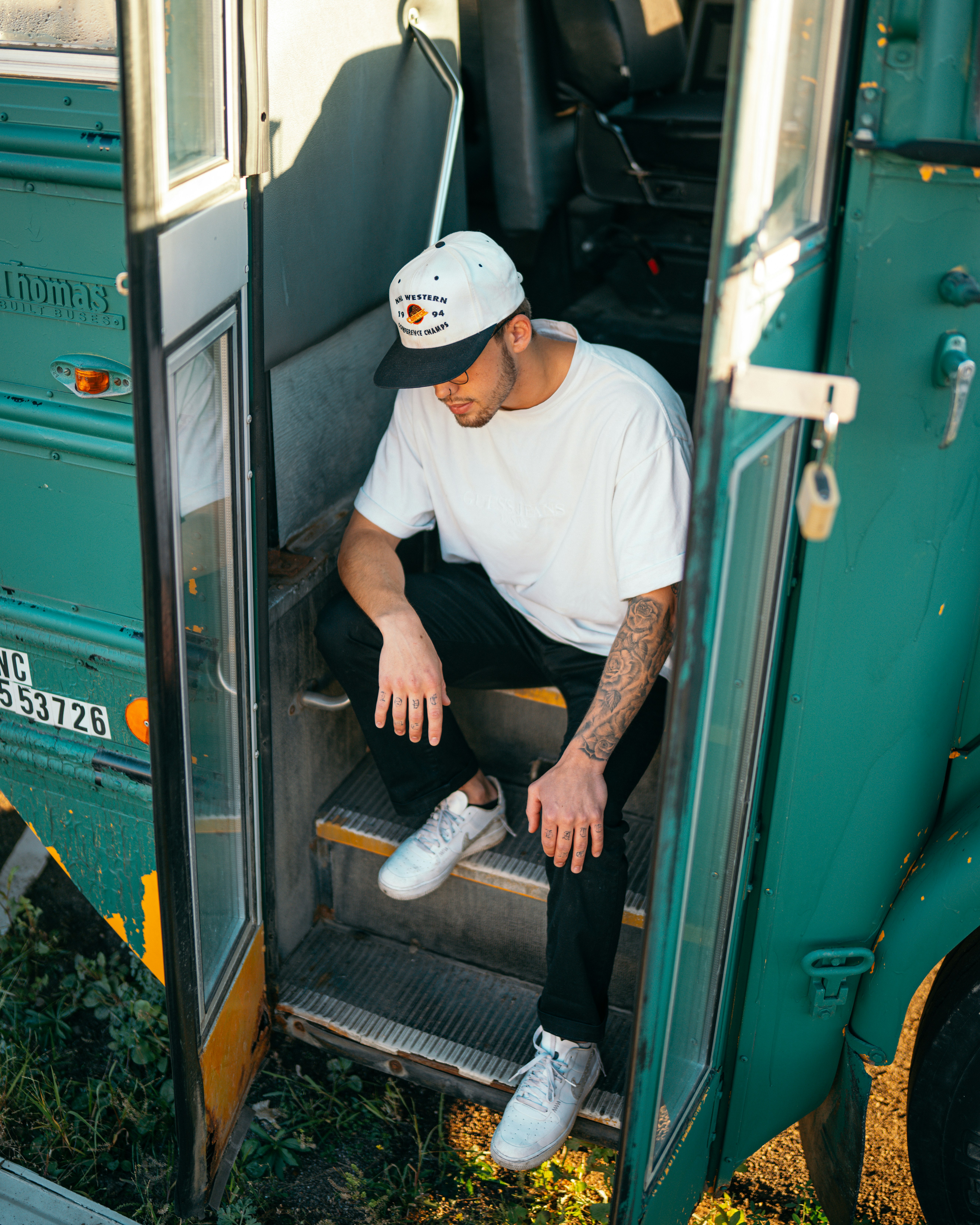 A man sitting on the steps of a green bus photo – Free Human Image on ...
