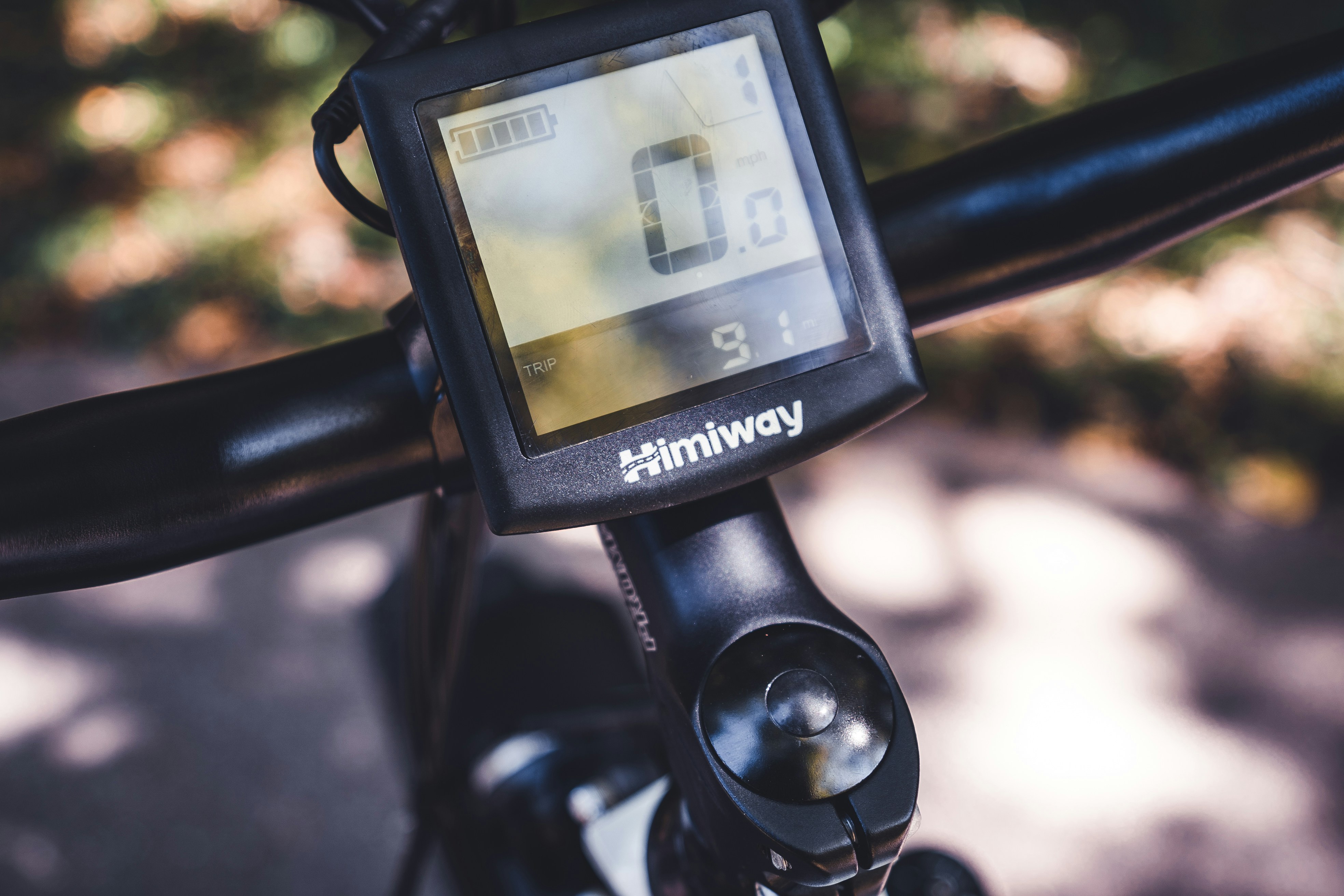 Close-Up on a Himiway Bike Computer Amid Sunlit Handlebar Blur