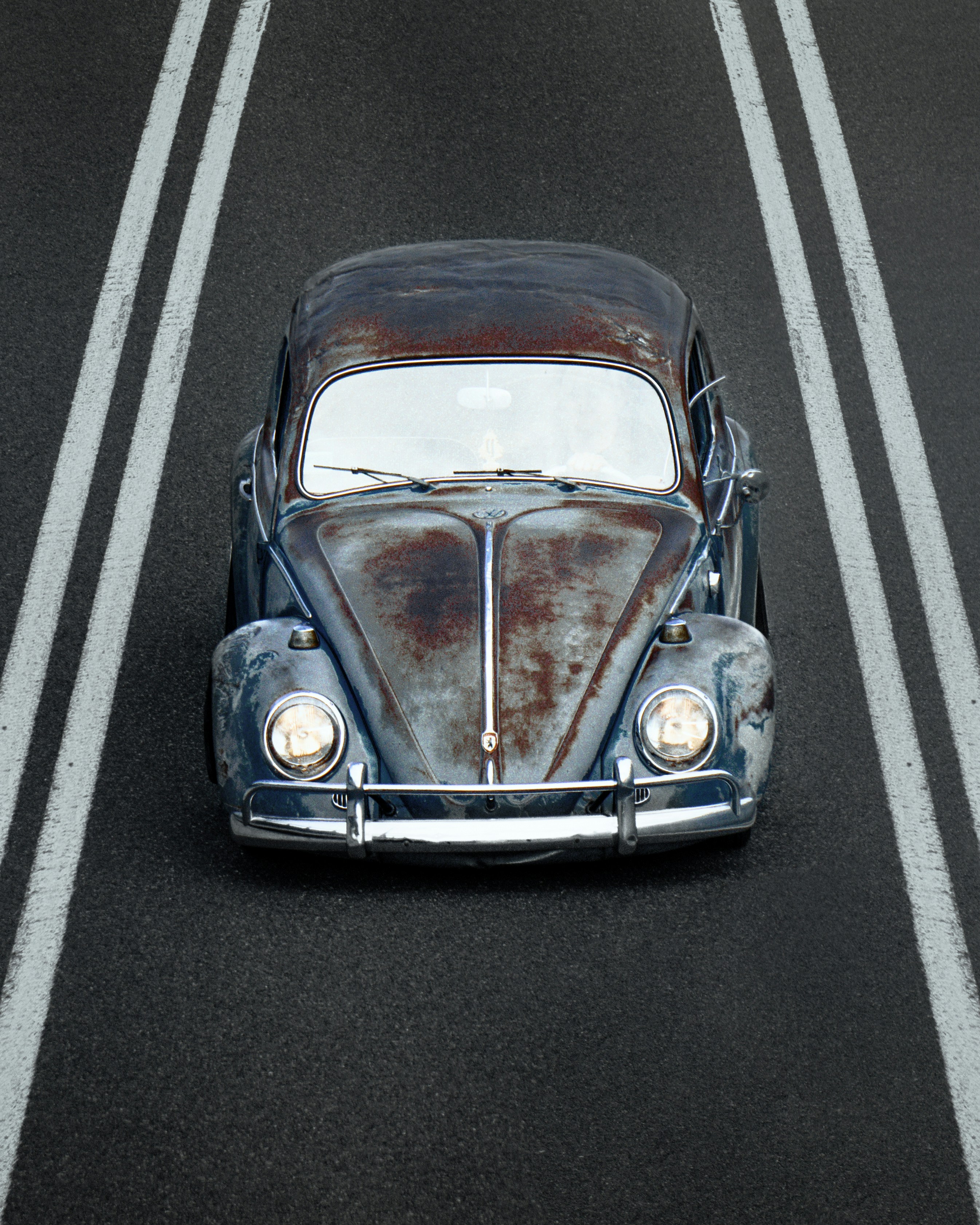 Aerial Portrait: Weathered VW Beetle Centered on Double White Lines