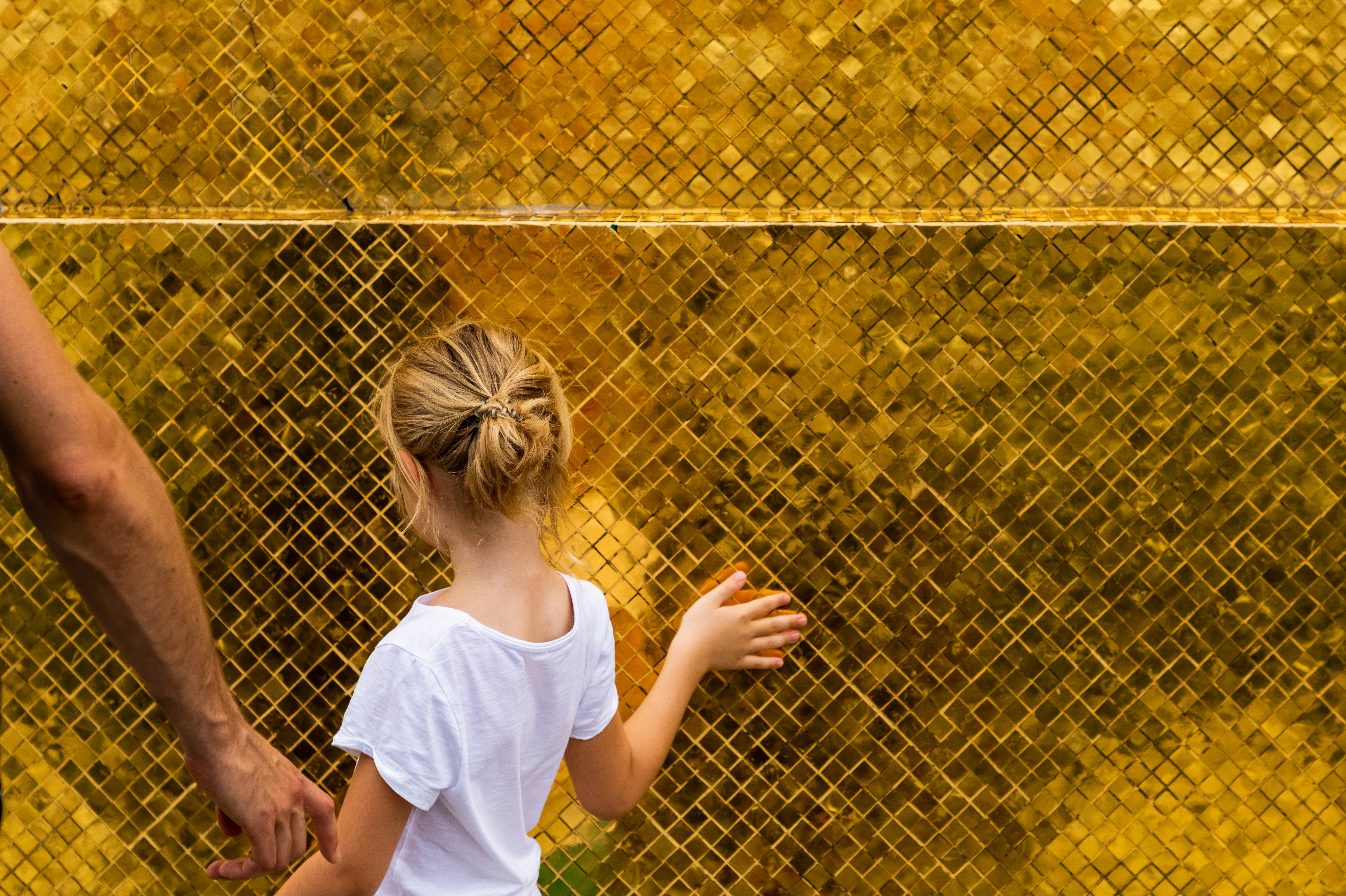 Child and guardian reach through a golden net of autumn light