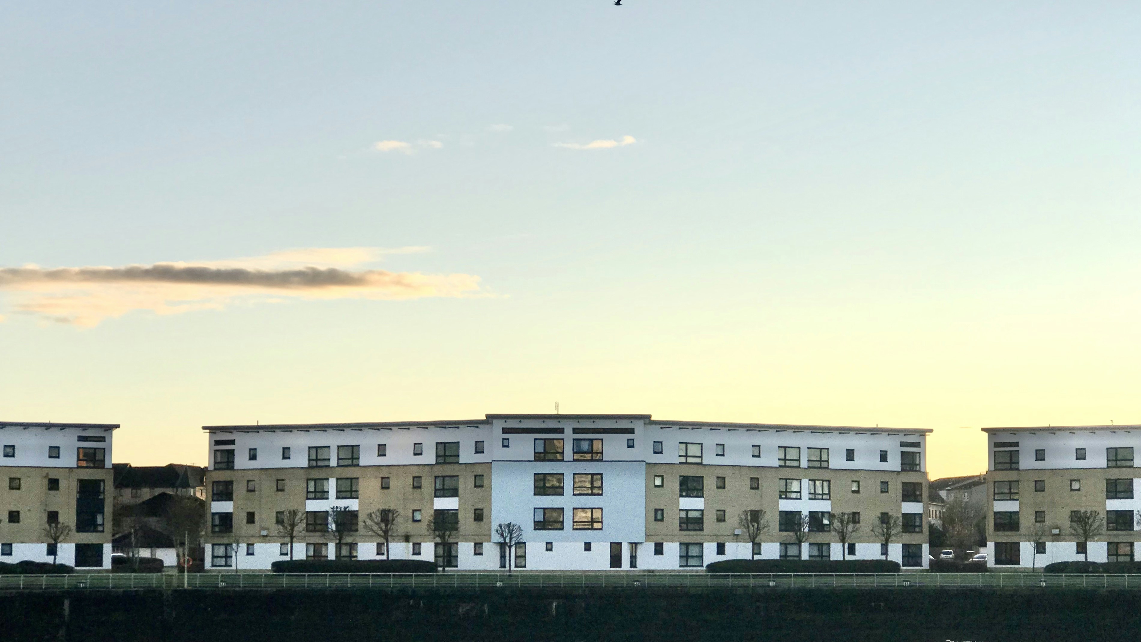 a plane flying over a row of apartment buildings