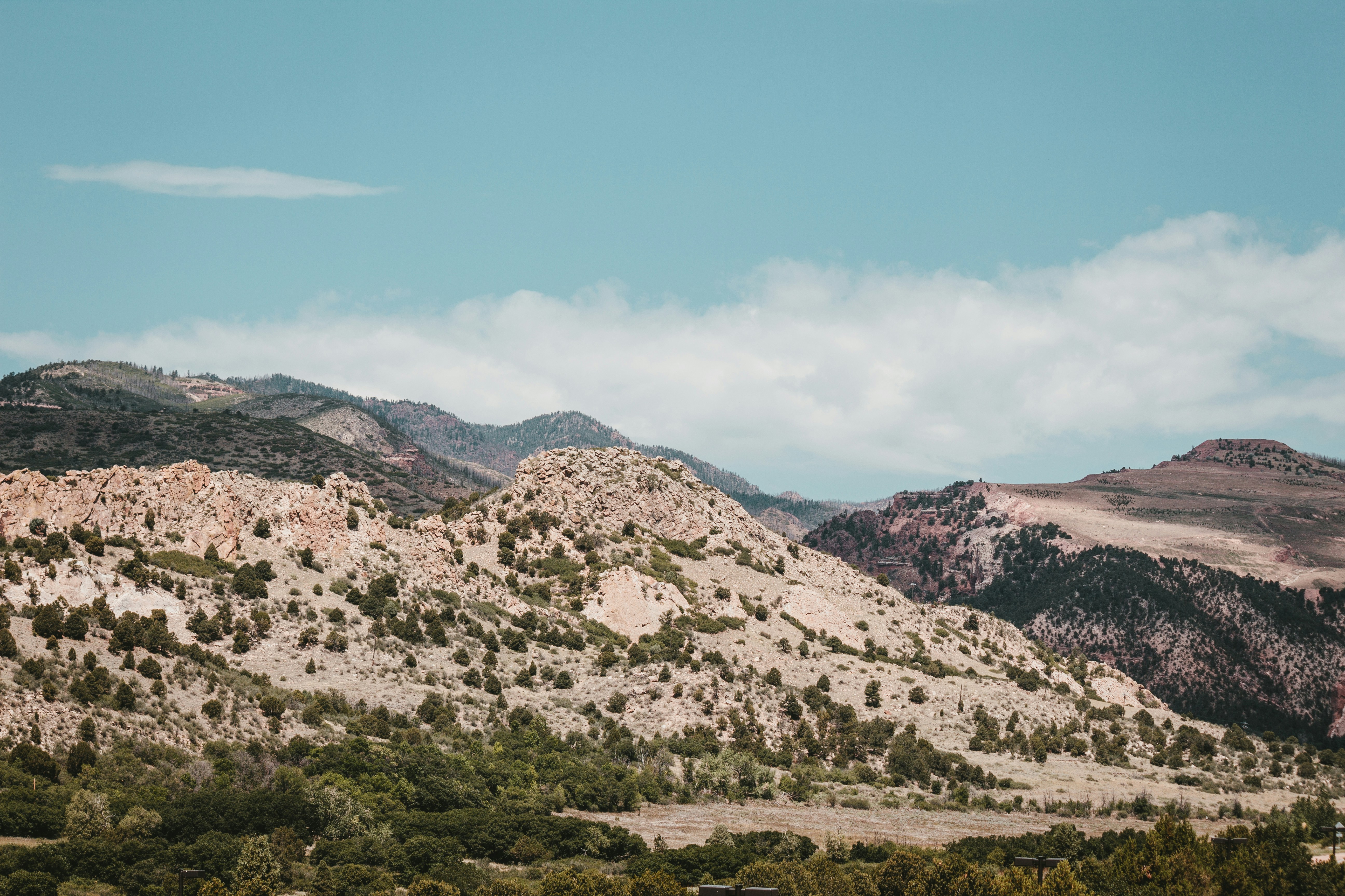 Vast rocky hills adorned with patches of greenery under a clear blue sky. The rugged landscape showcases the natural beauty of mountainous terrain.