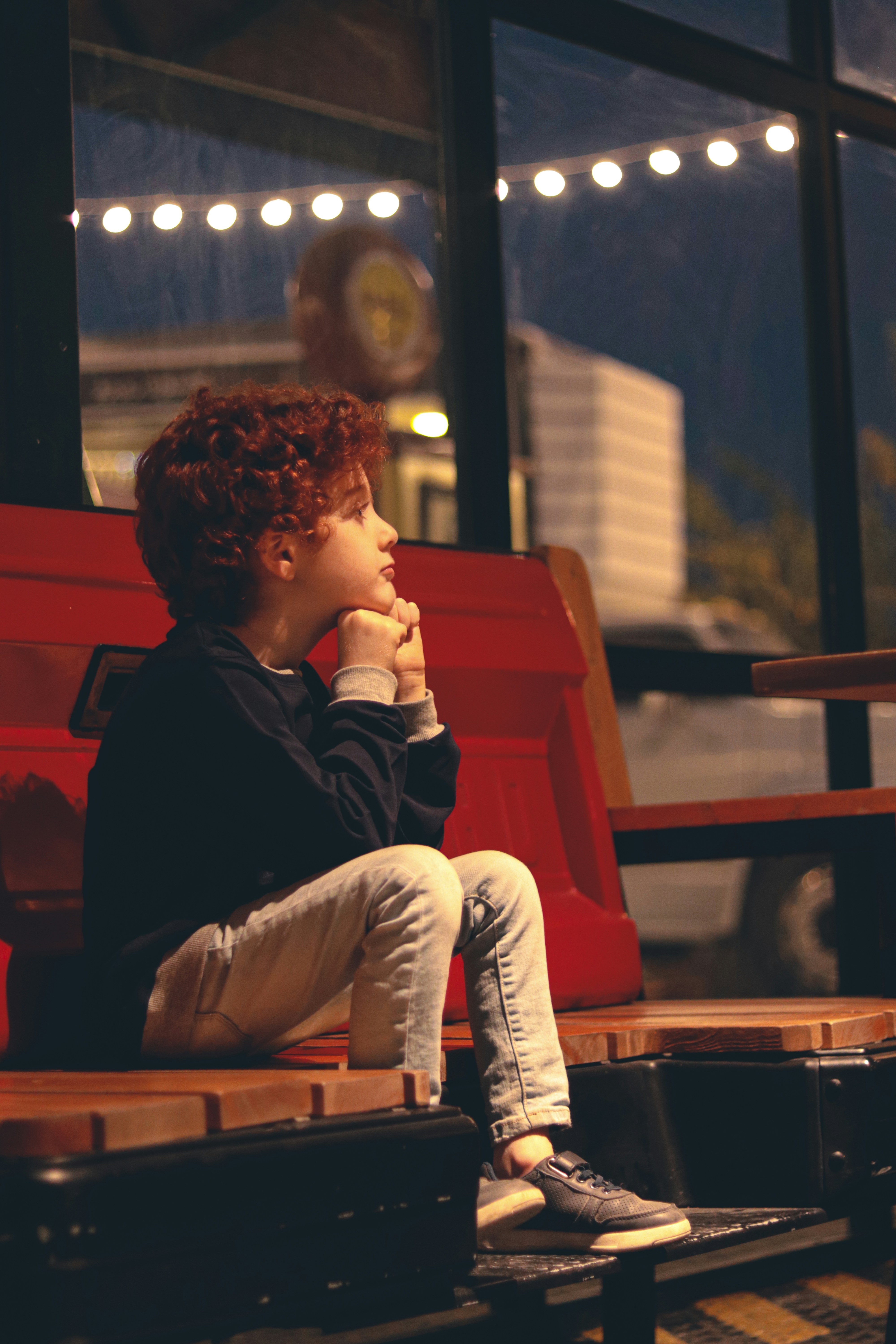 Profile in Warm Neon: A Child Pauses on a Red Bench