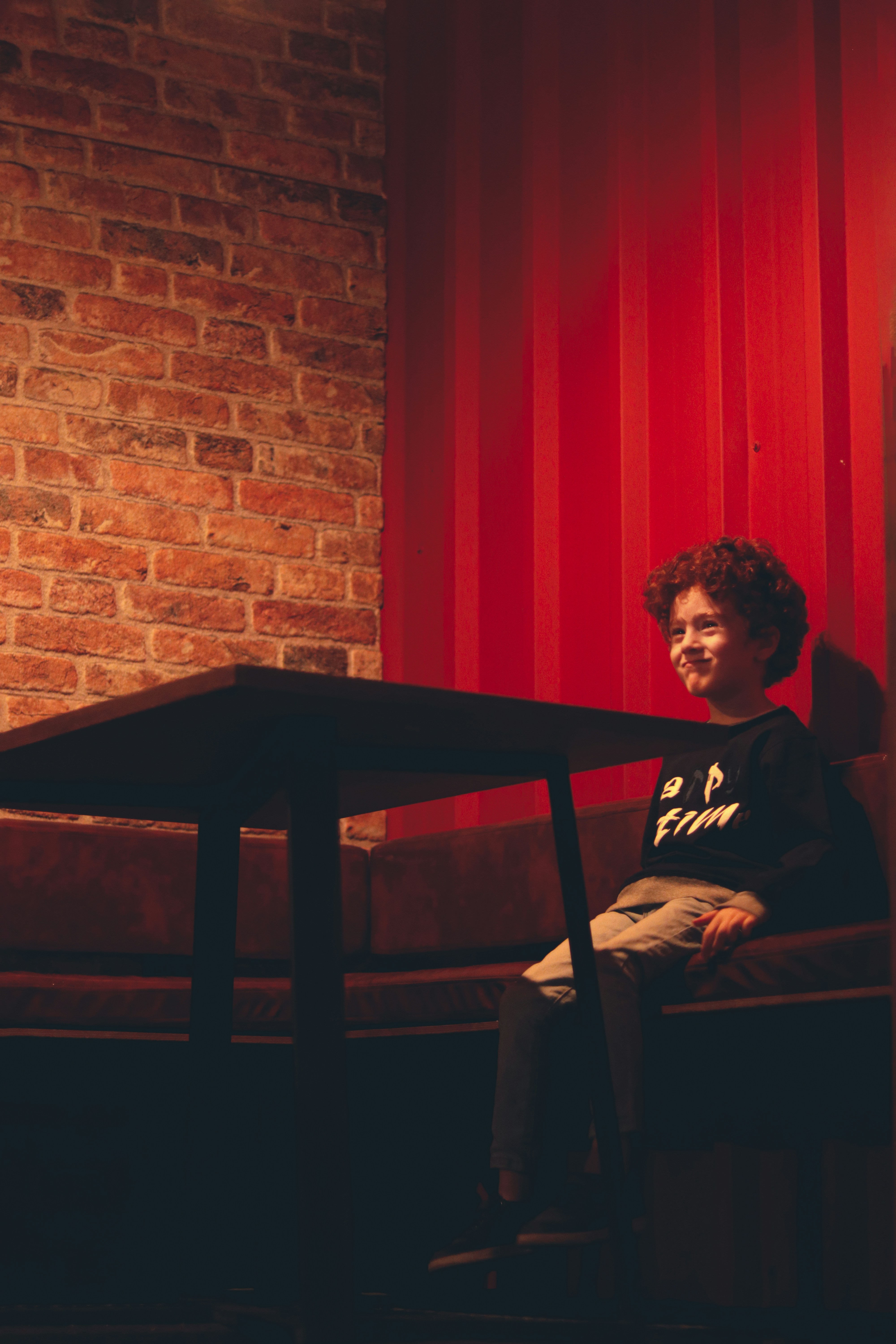 Un homme assis à une table devant un mur de briques rouges photo ...