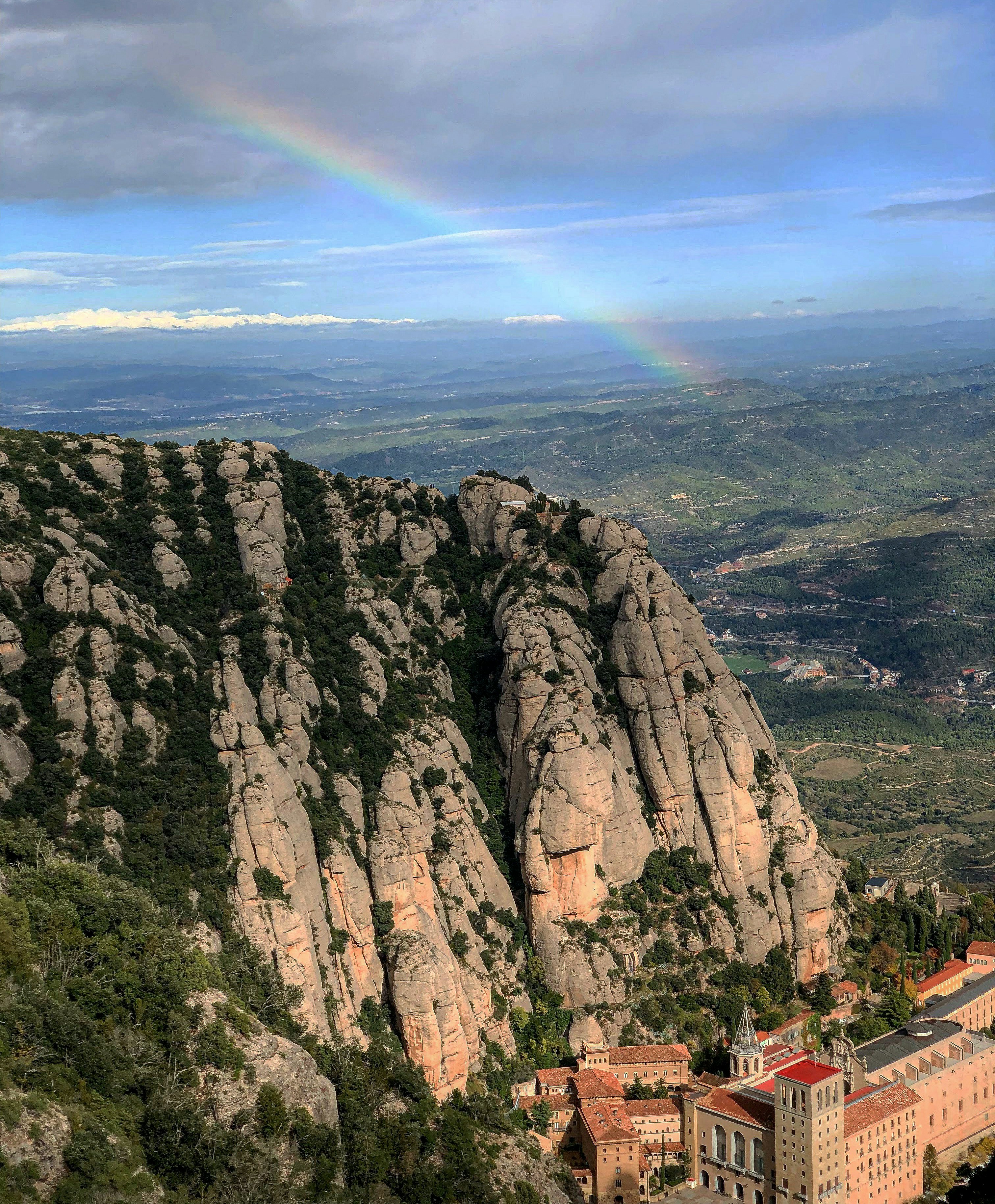 Rainbow over rugged cliffs and a terracotta monastery