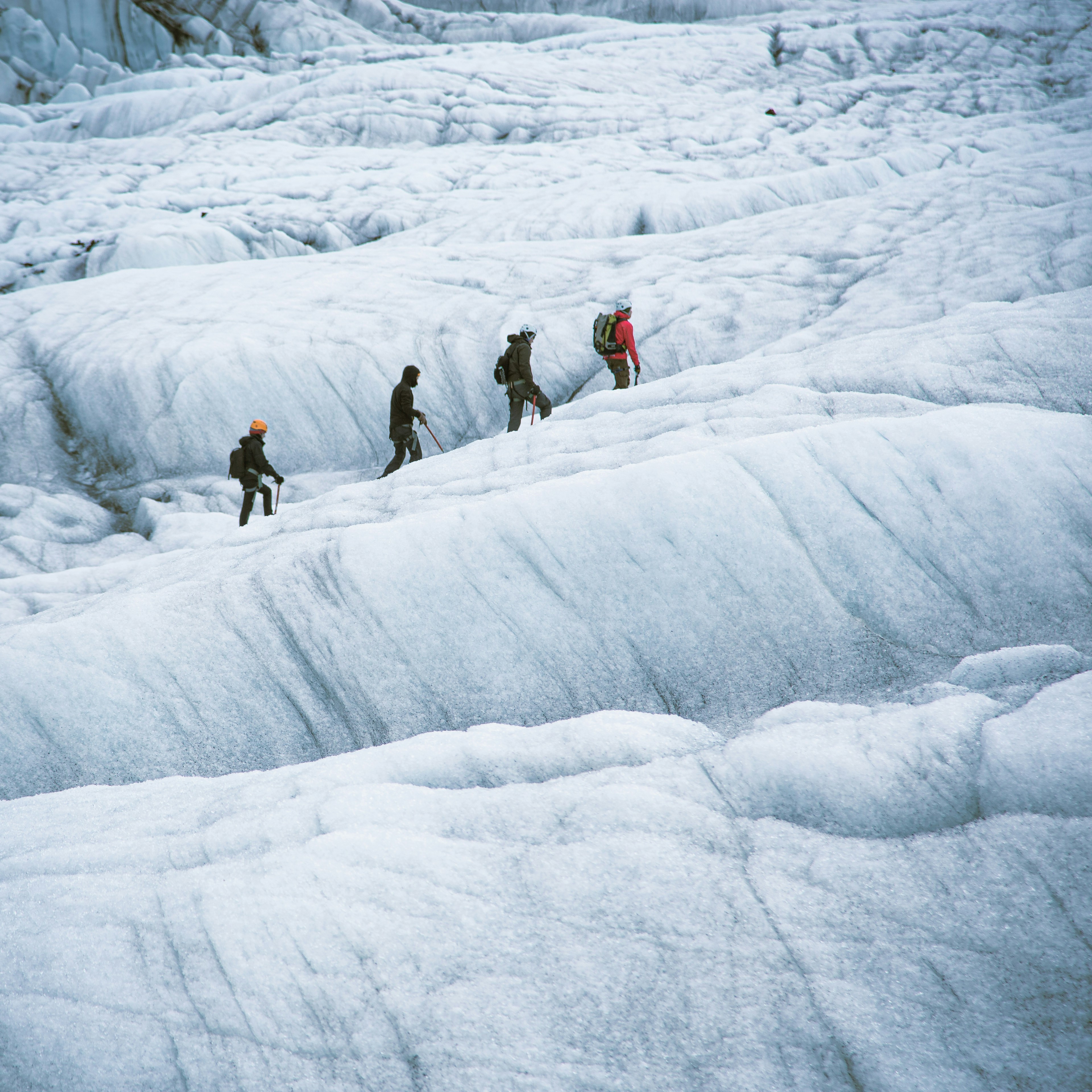Group of climbers traversing a vast glacier, showcasing the rugged textures and icy formations of the landscape.