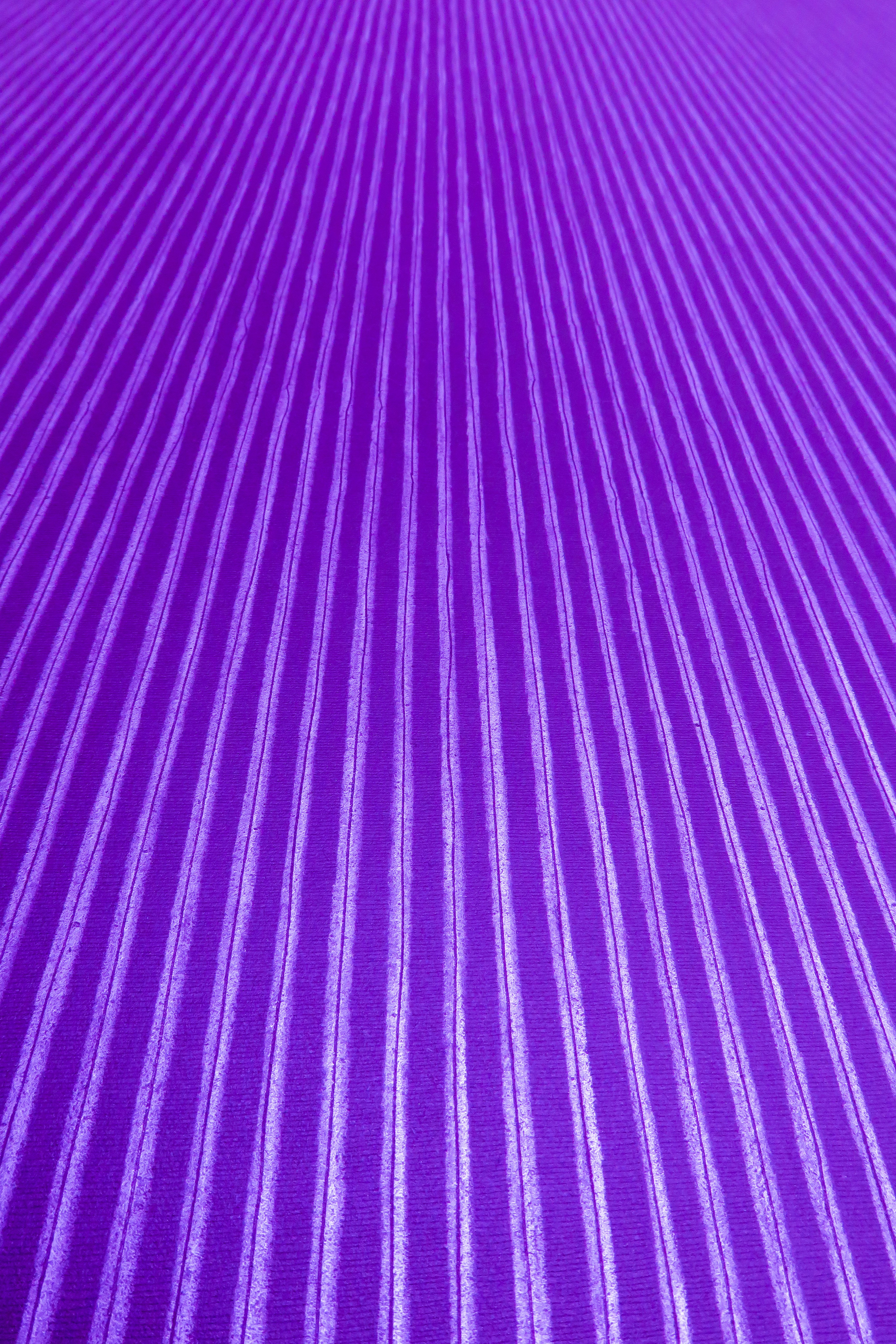 A textured surface featuring vertical stripes in varying shades of purple, creating a rhythmic pattern that draws the eye.